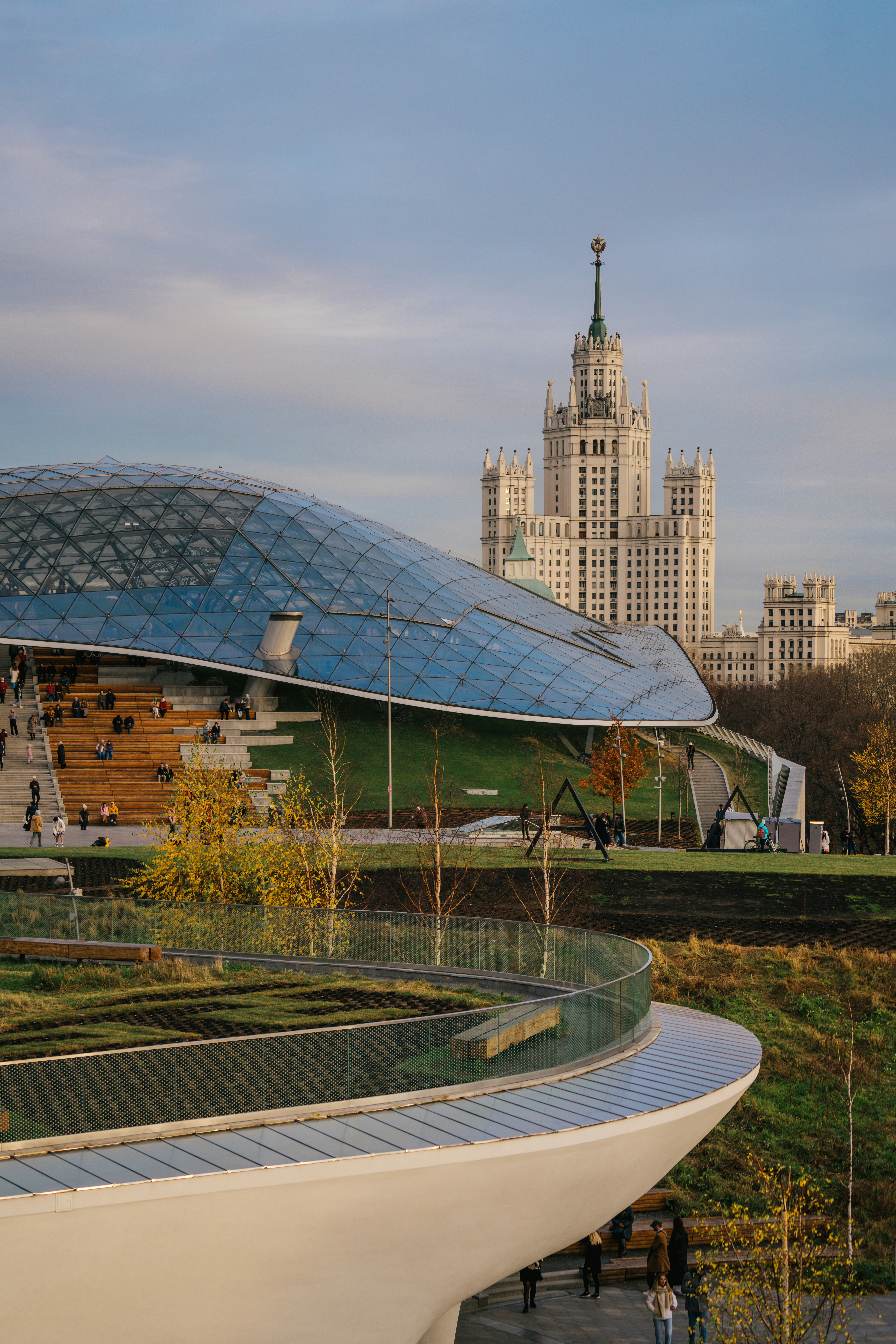Glass Canopy Over a Terraced Park Framing a Historic Skyline