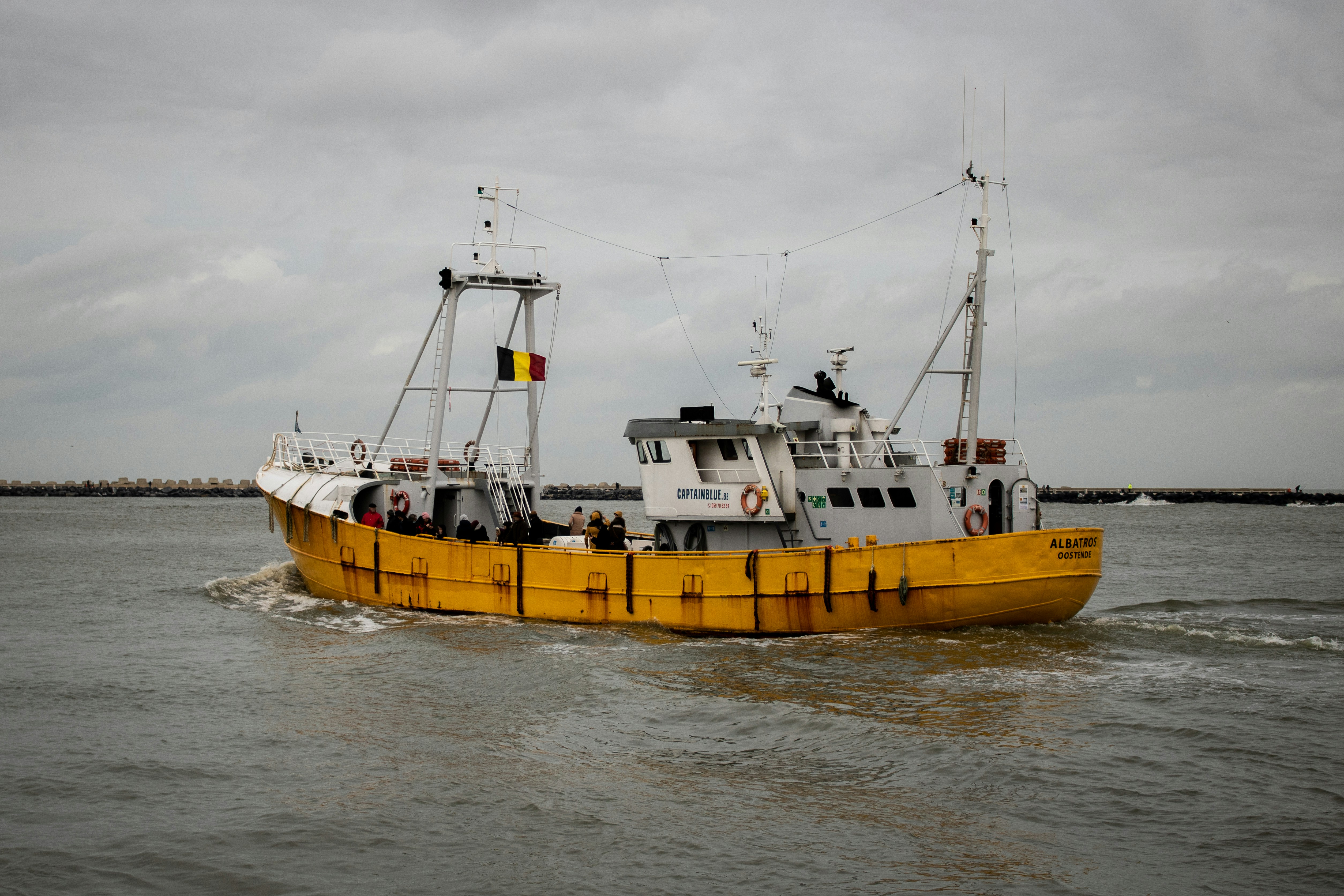 Yellow fishing boat navigating through calm waters under an overcast sky, showcasing the maritime spirit and daily life at sea.