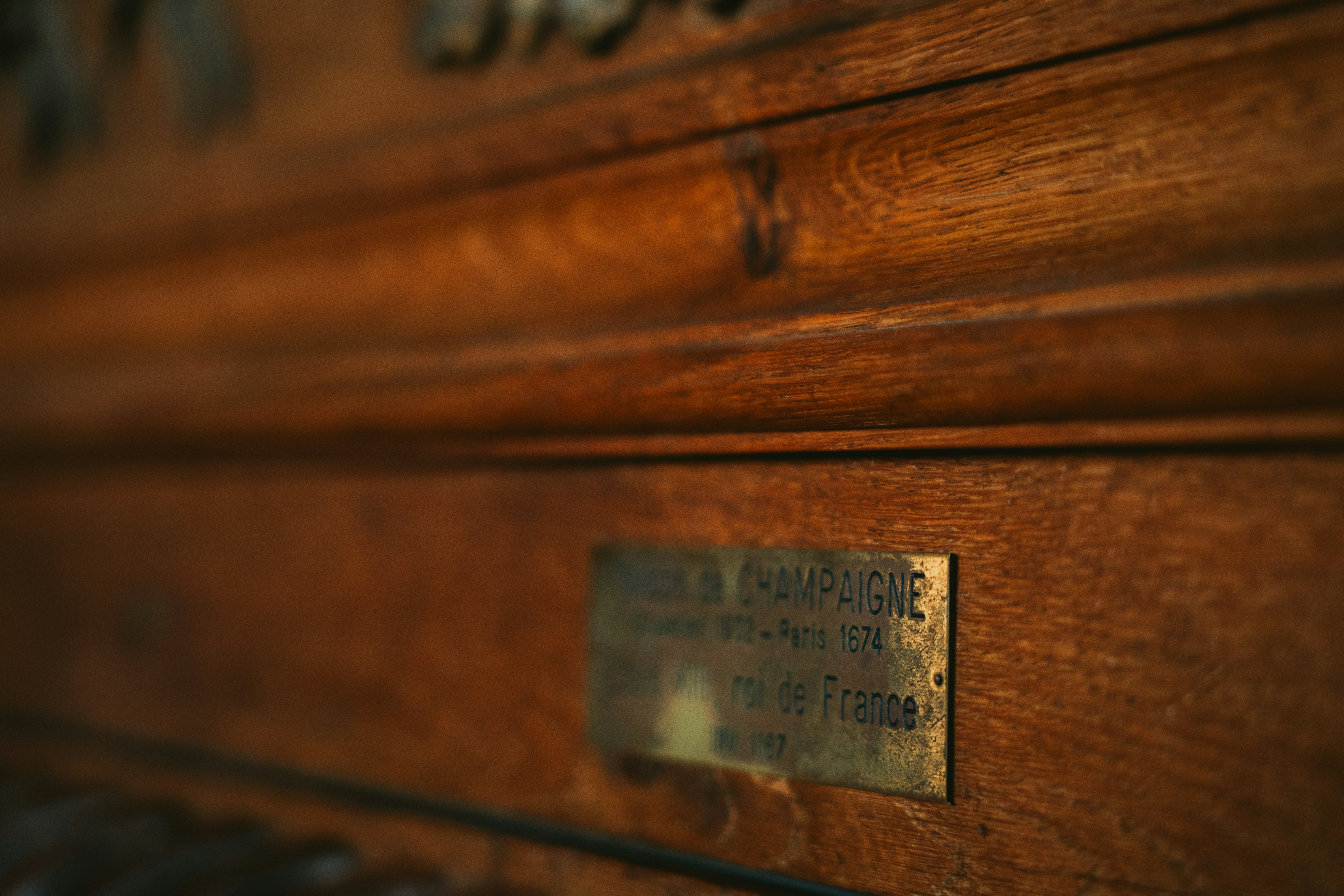 Close-up of an antique piano's nameplate, highlighting intricate details and craftsmanship. The brass plate reveals the maker's name and origin.