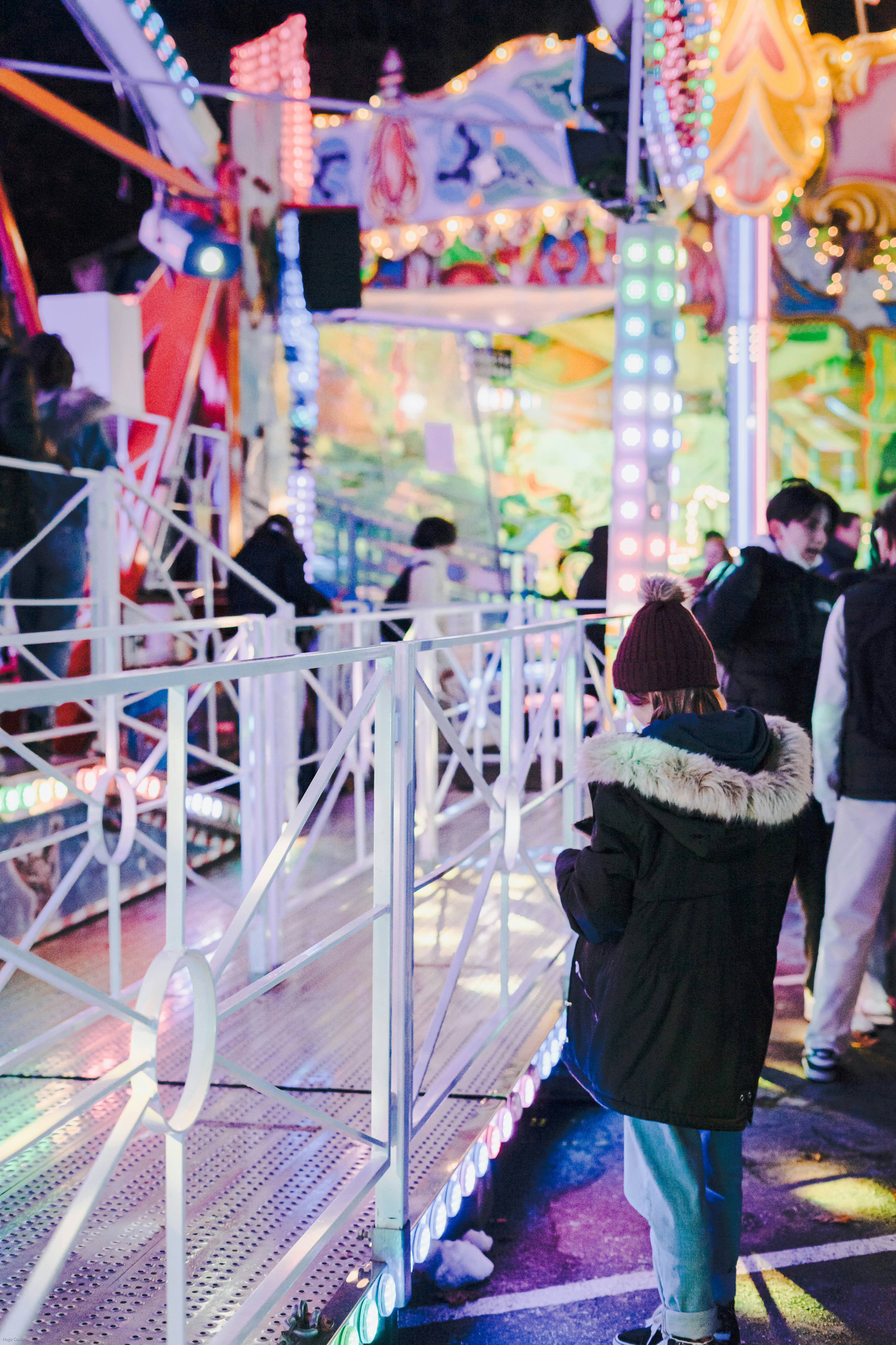 A group of people standing around a carnival ride photo – Free City ...