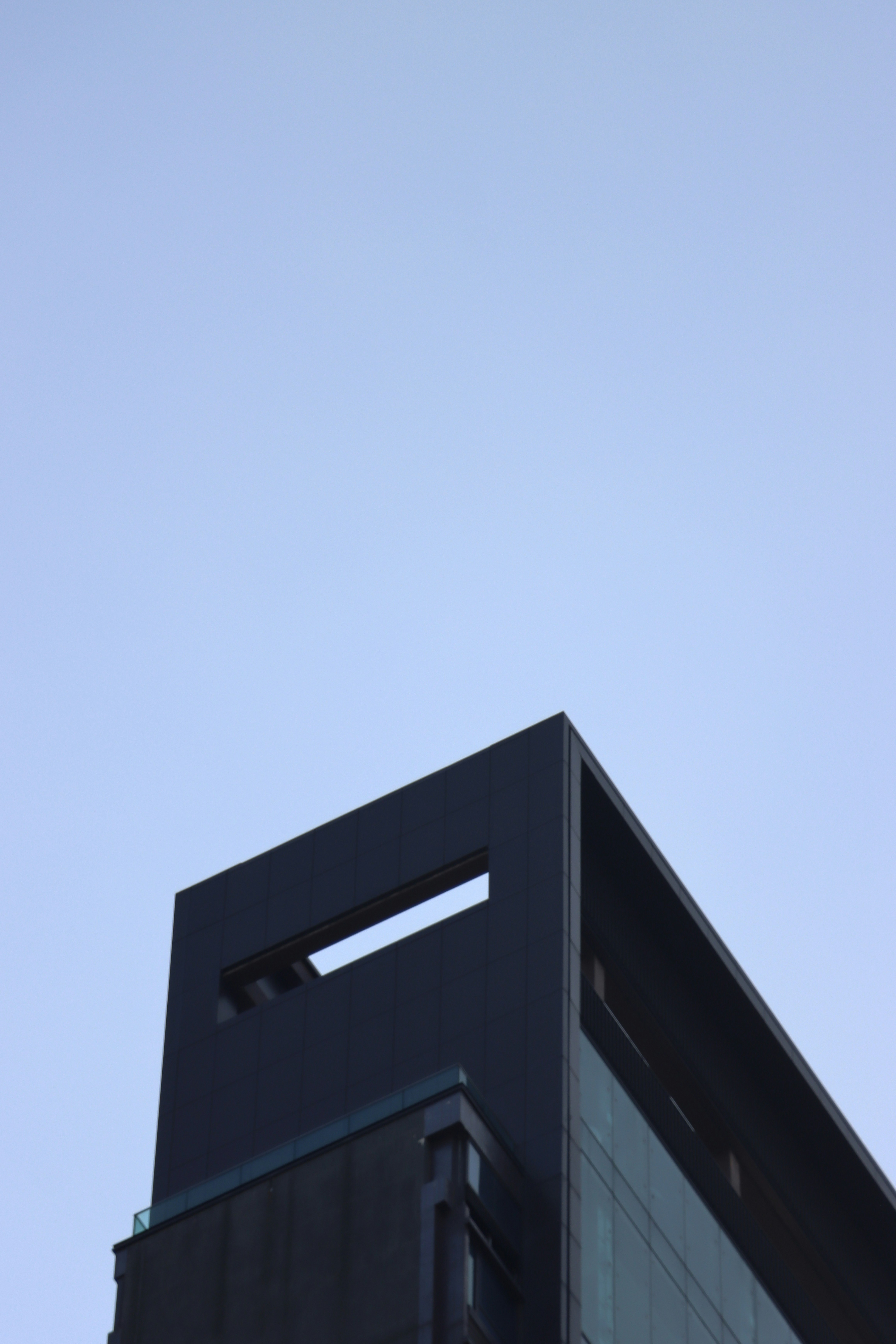 A sleek, modern building corner with a distinctive cut-out design against a clear sky.