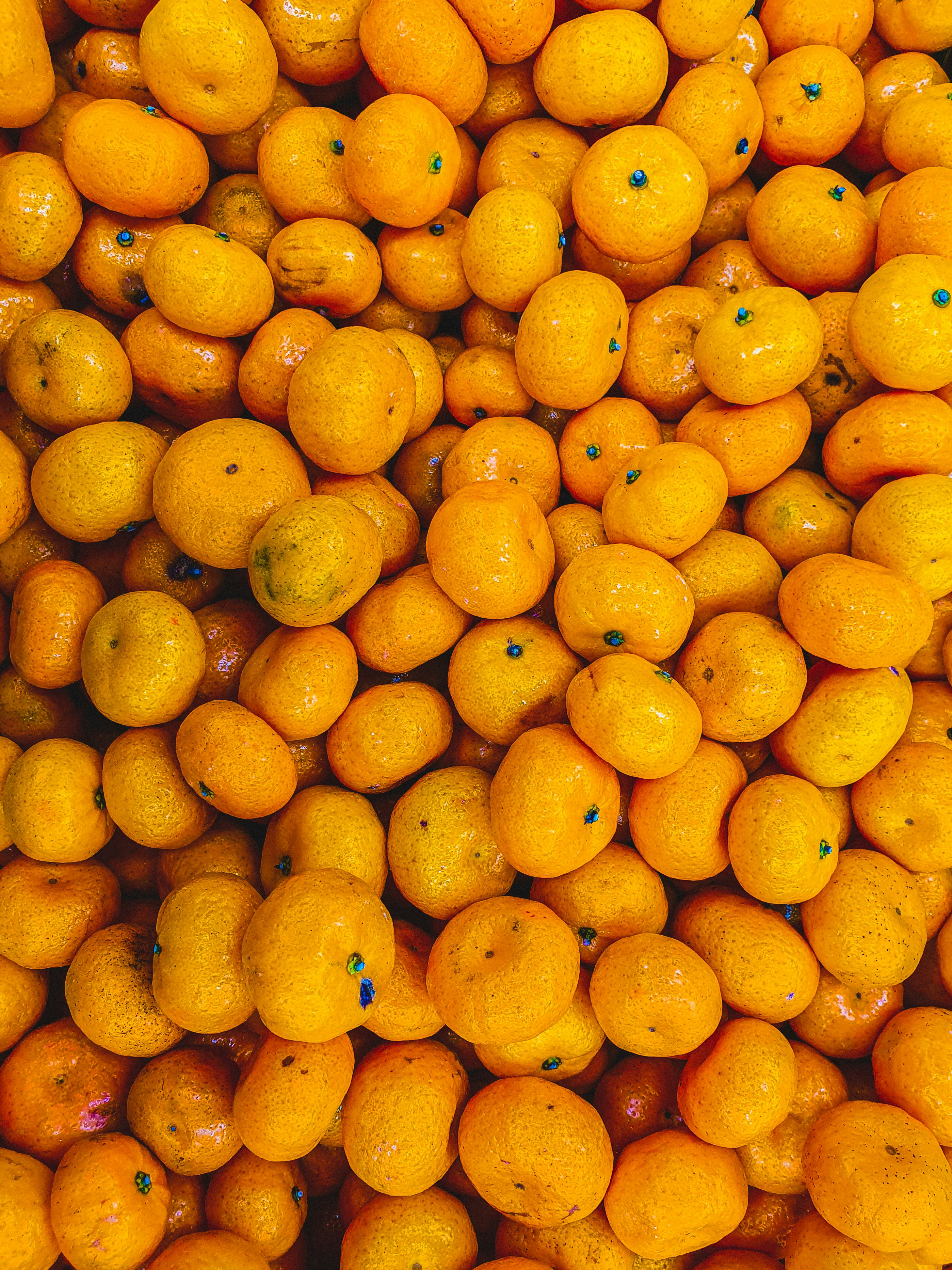 A dense arrangement of bright orange mandarins, showcasing their textured skins and rich colors. The scene captures the essence of freshness and abundance.
