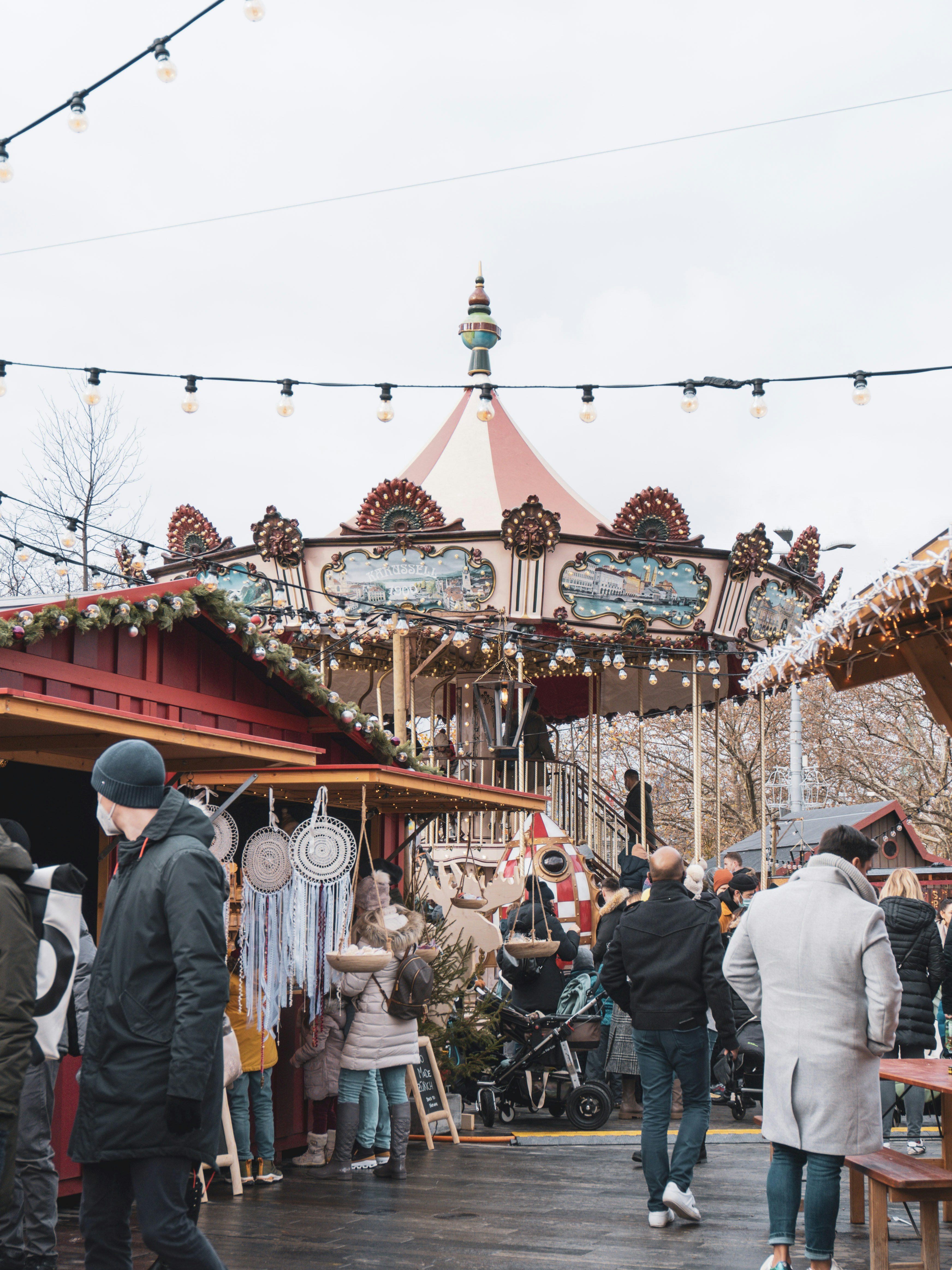 A group of people standing around a merry go round photo – Free ...