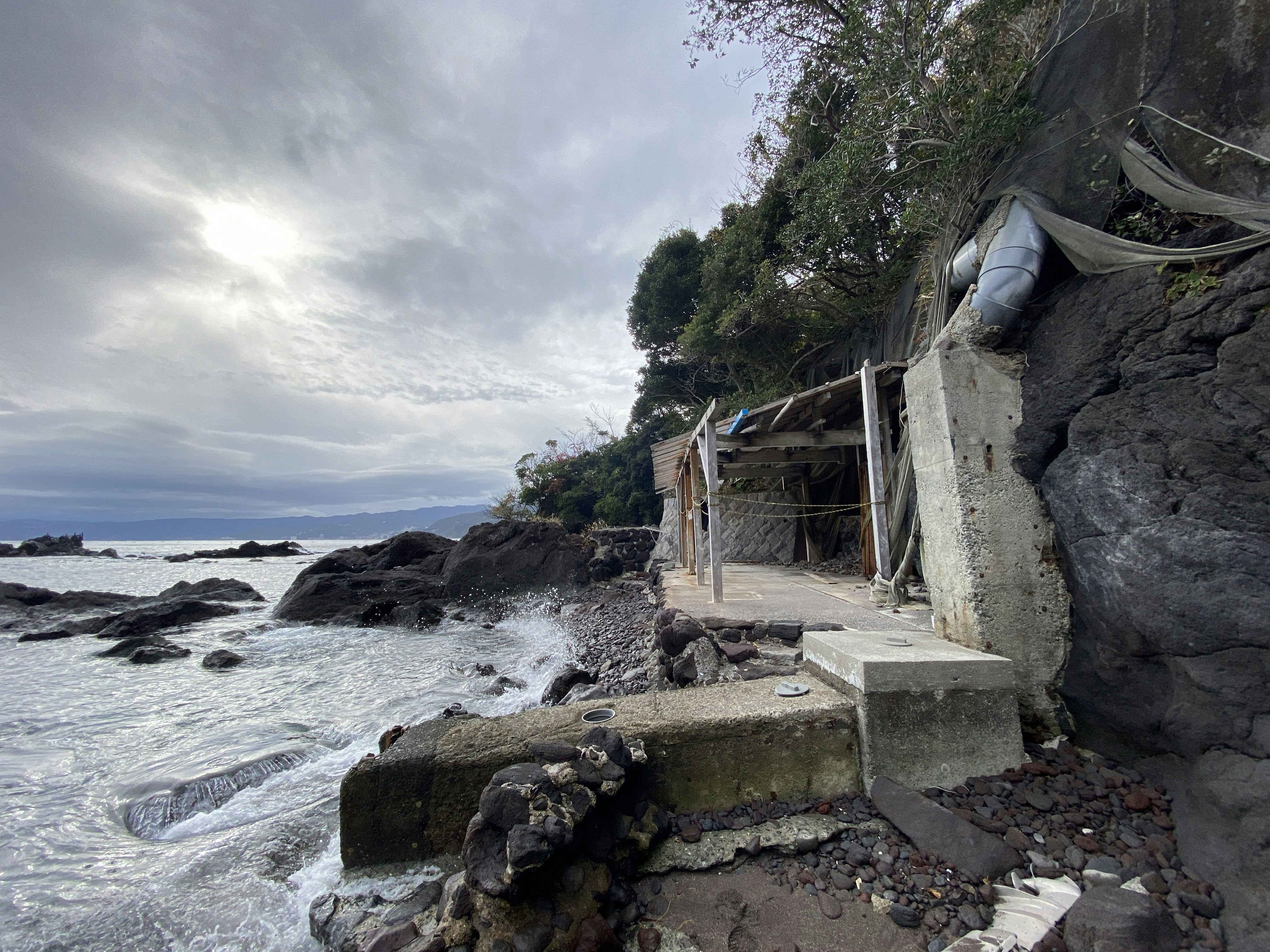 Demolished remnants of a building on the coast of the Manazuru Peninsula, Kanagawa Prefecture, Japan | a rocky shore line with a house on it