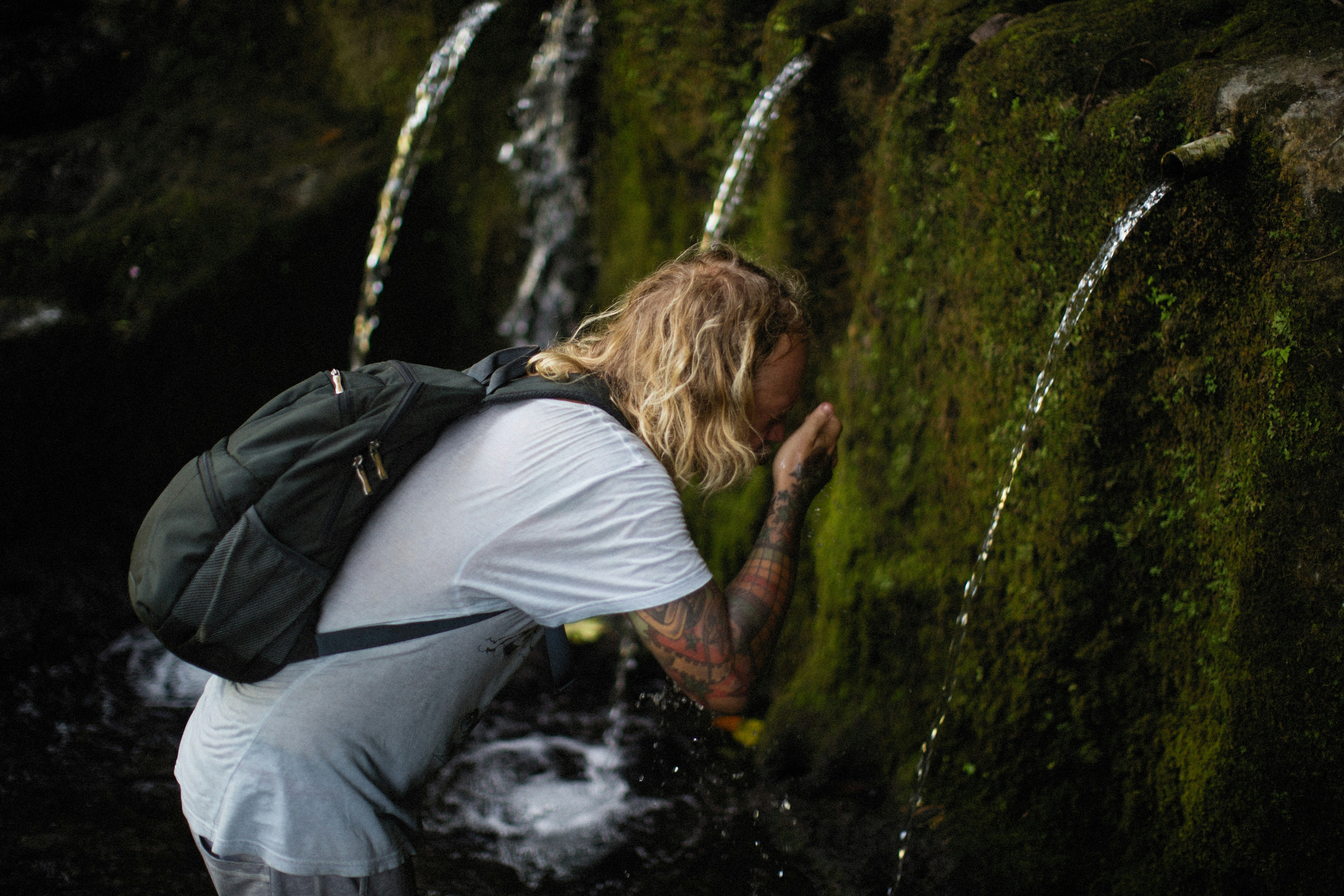 Whispering Moss: A Traveler at the Mossy Waterfall Wall