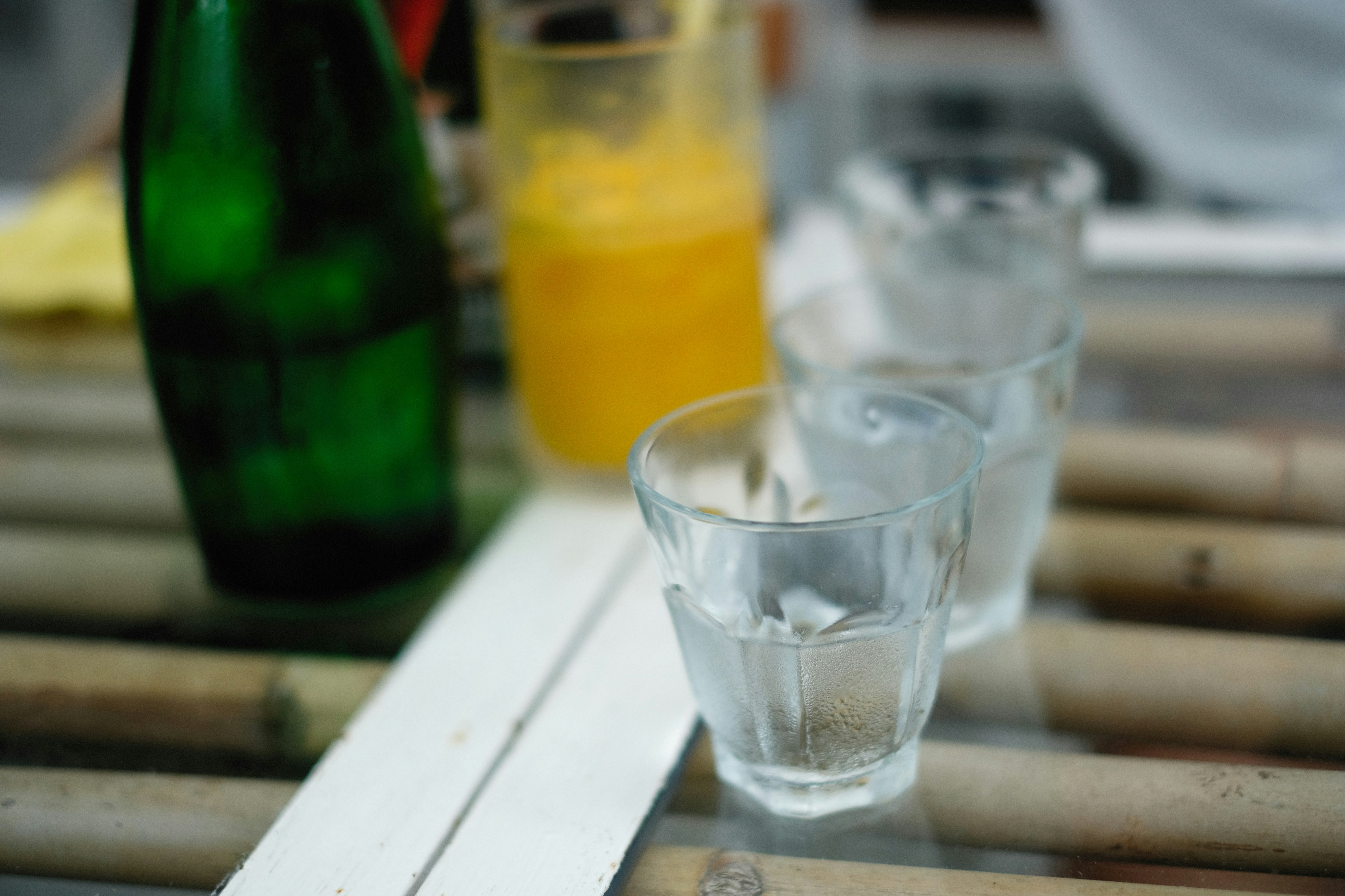 Glassy Reflection and Bottled Cheer on a Bamboo Table