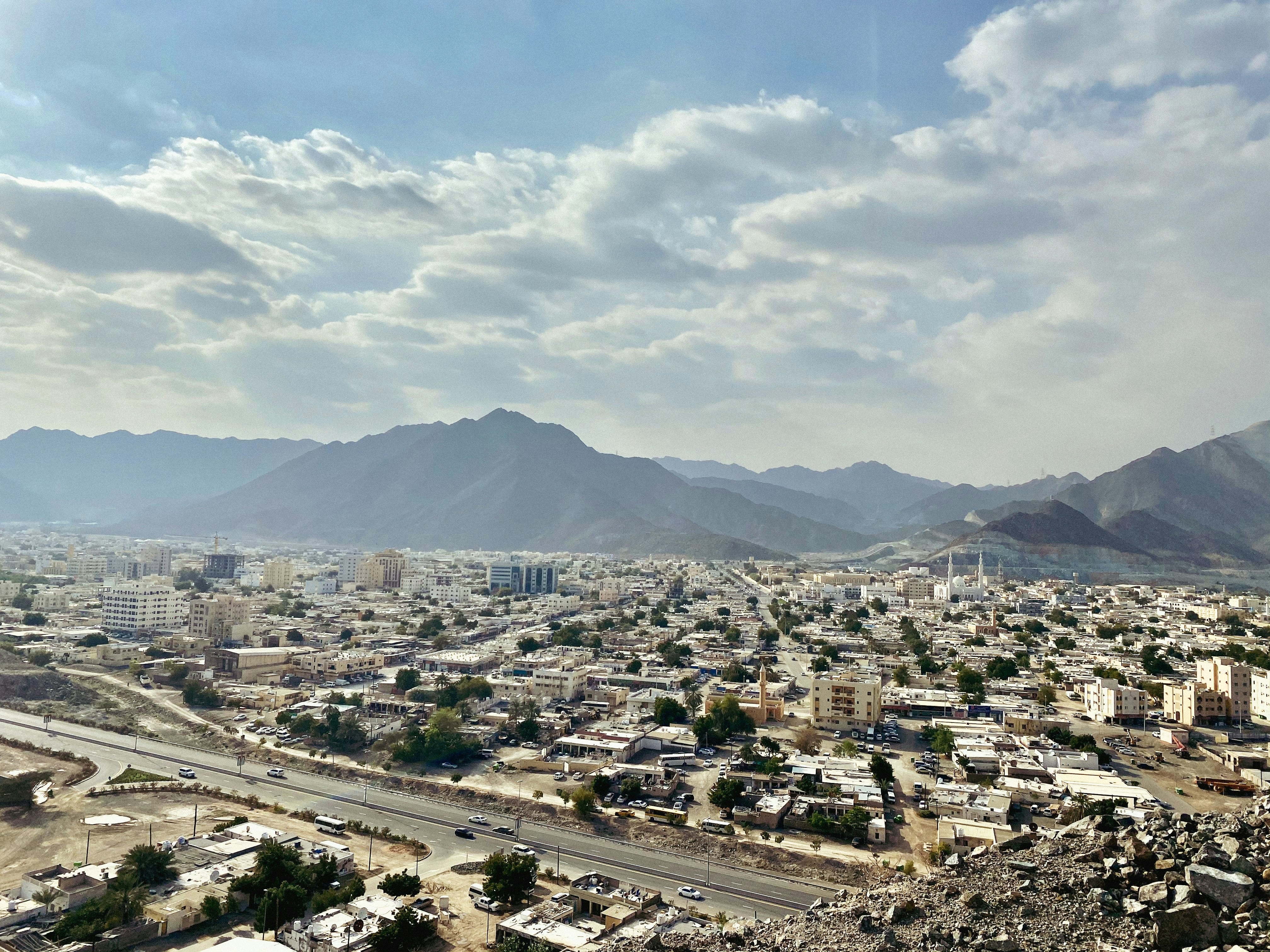 Expansive view of a city nestled between towering mountains, showcasing a blend of urban architecture and natural beauty.