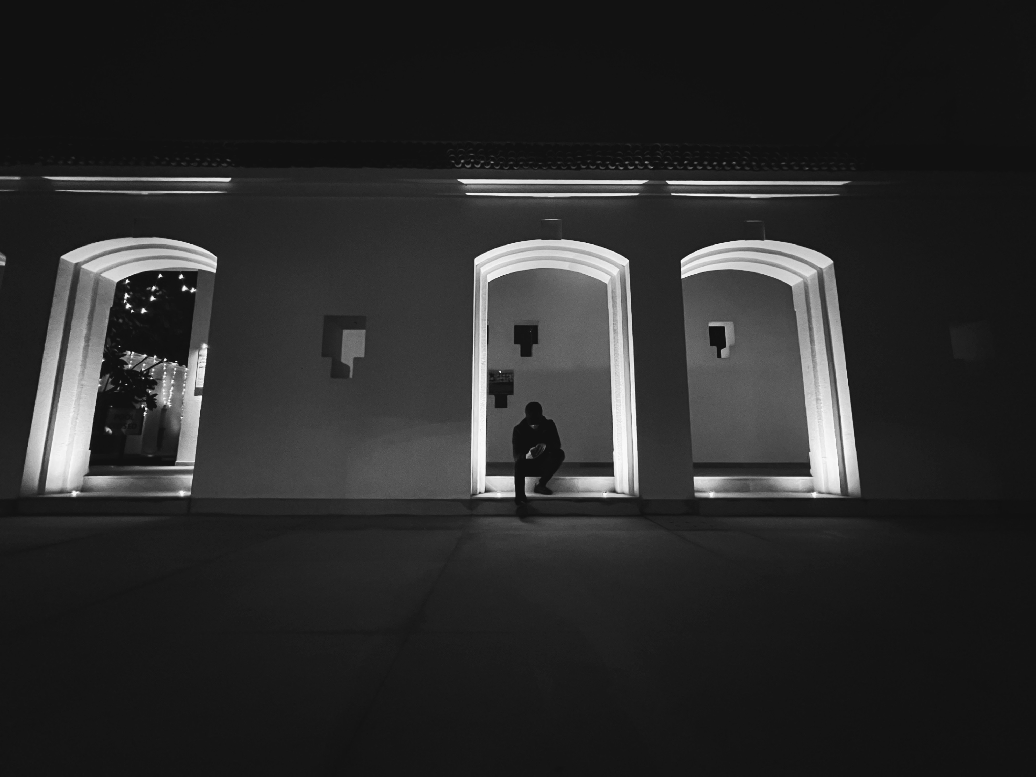 A person standing outside of a building at night photo – Free Wallpaper ...