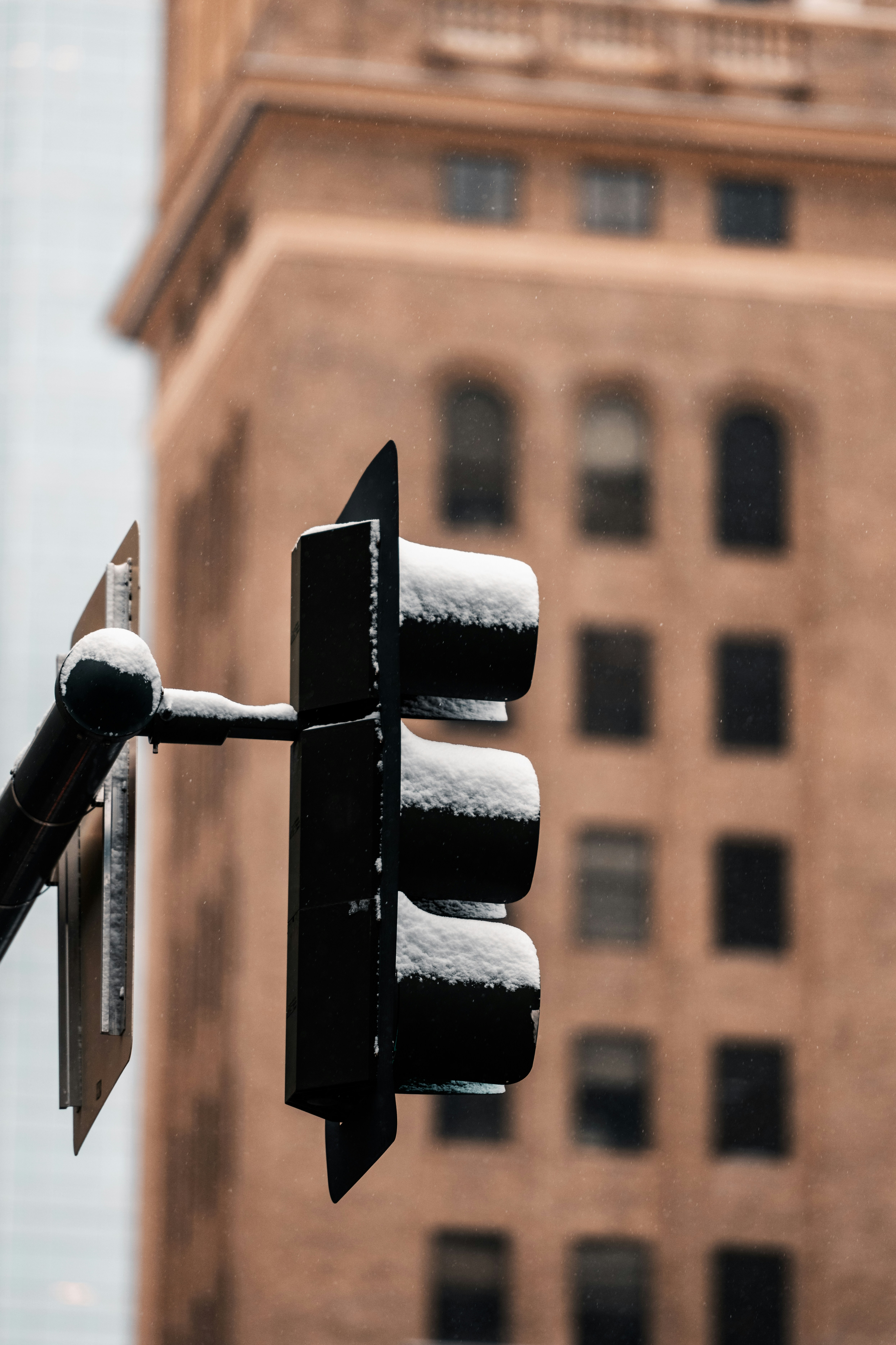 Snow-Dusted Signal: A Close-Cropped View of Urban Traffic Light Against Brick Facade