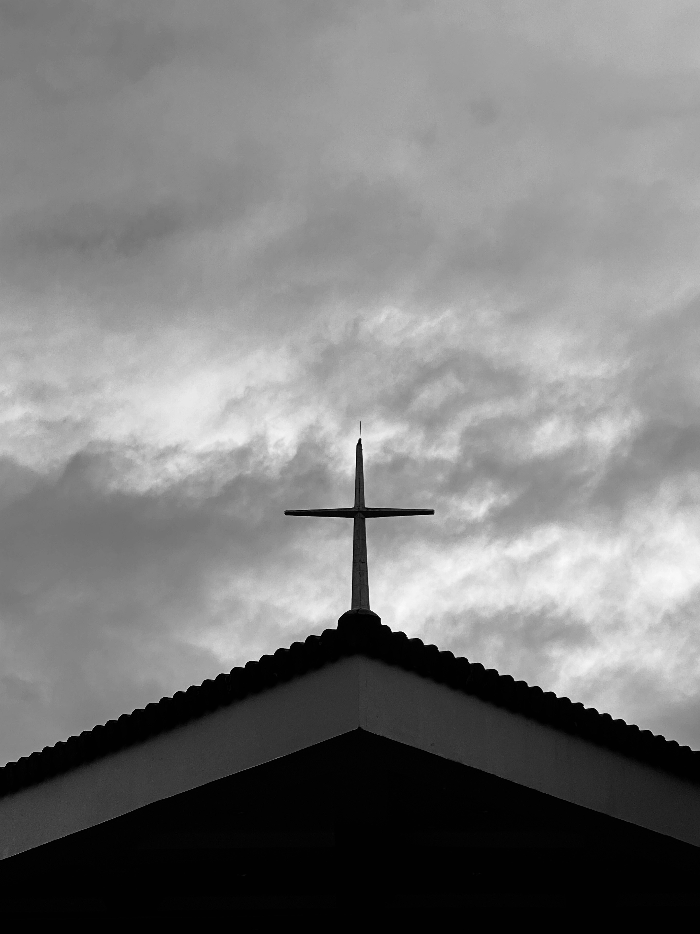 a black and white photo of a cross on top of a buildingethan