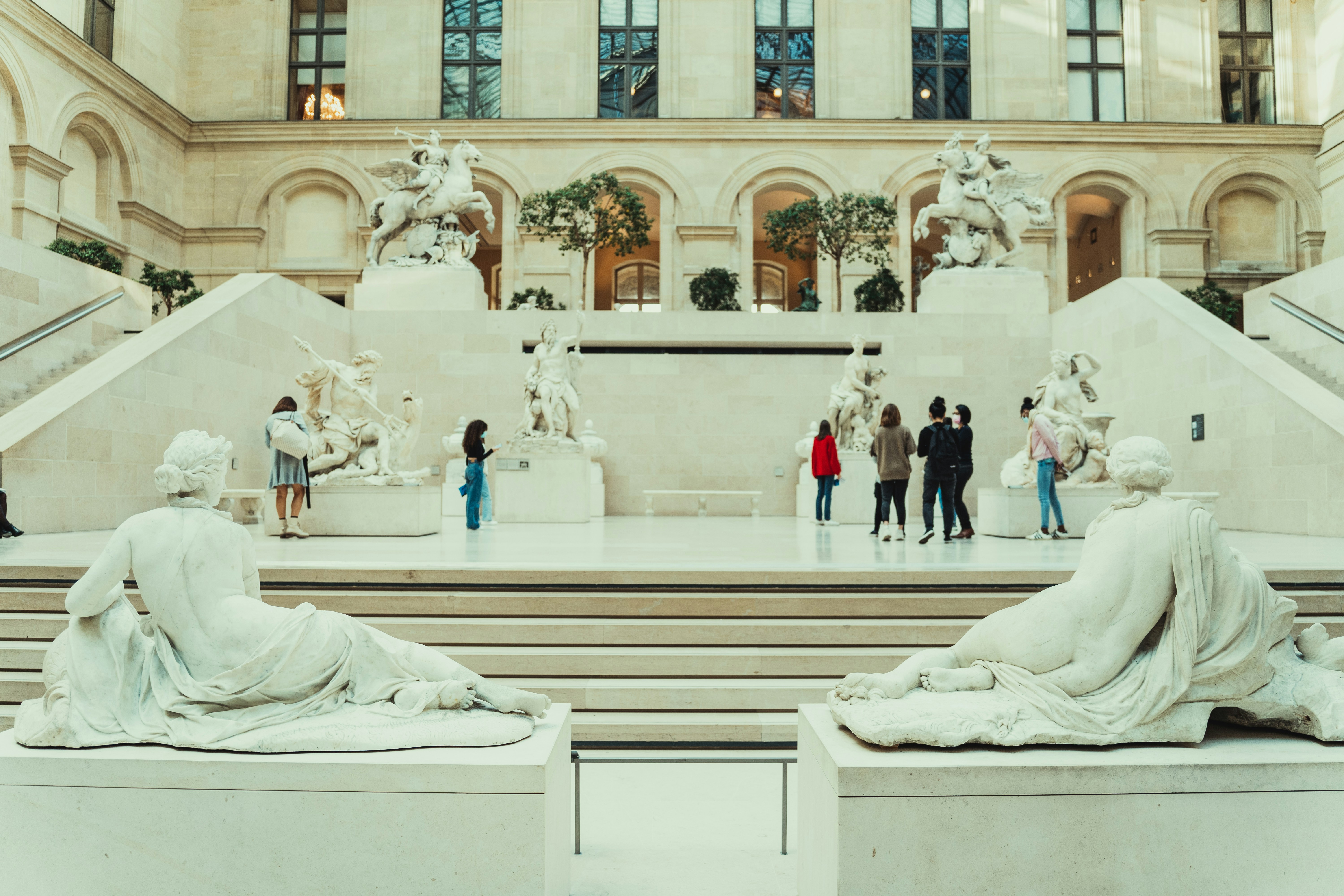 A group of people standing around statues in a building photo – Free ...