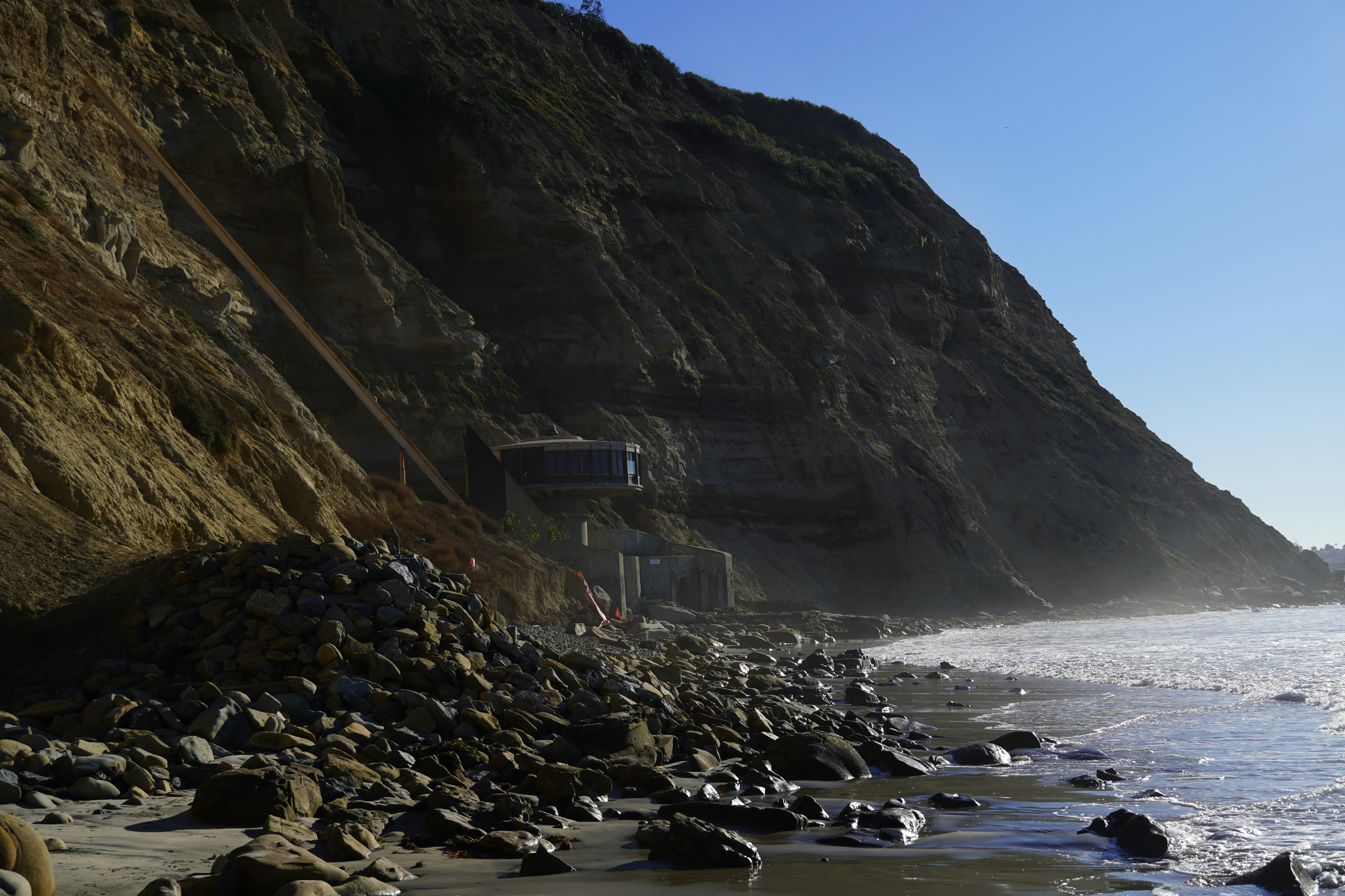 Cliffside Cabin Perched Above a Pebble Shore