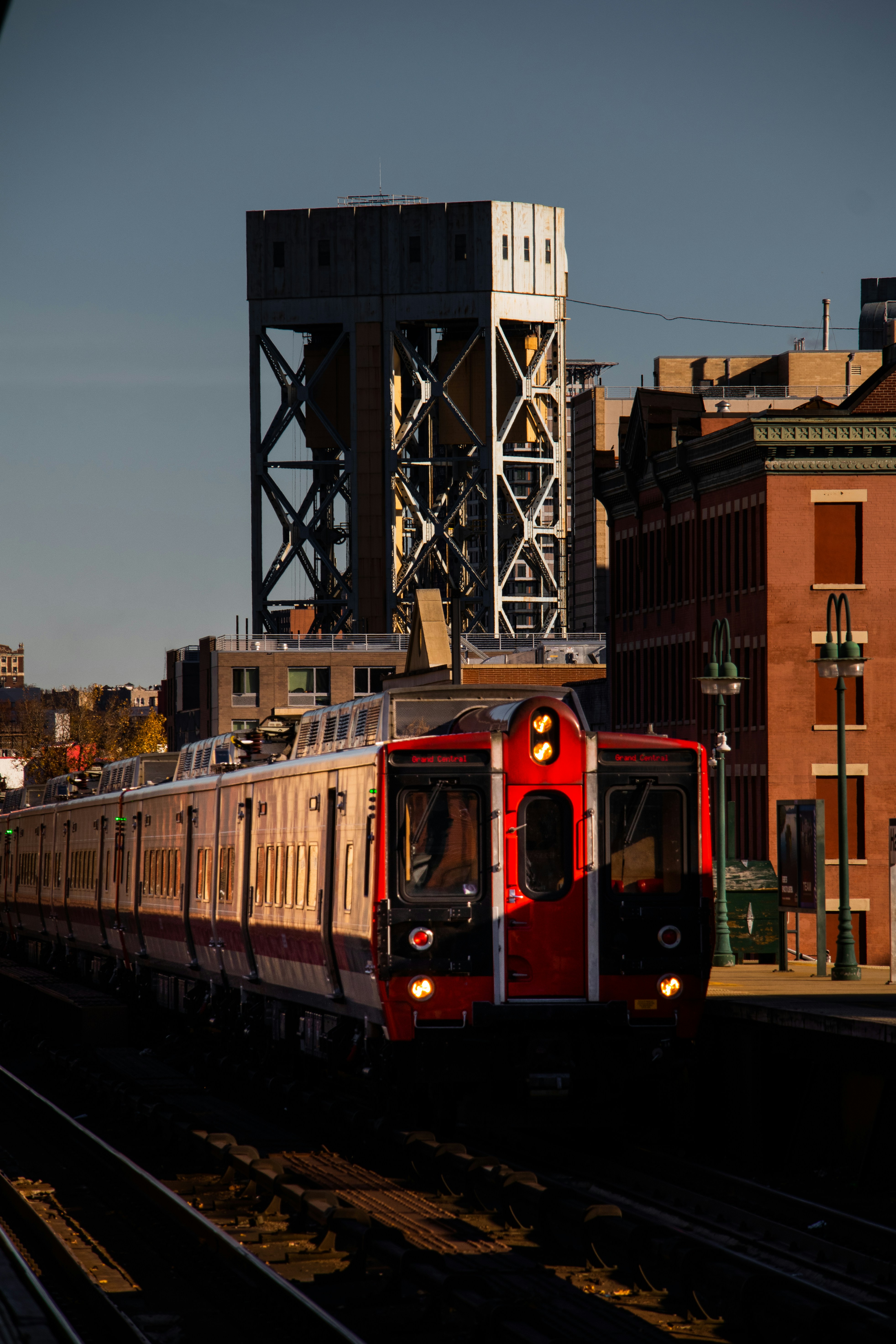 Red commuter at dusk: urban tracks beneath a steel tower