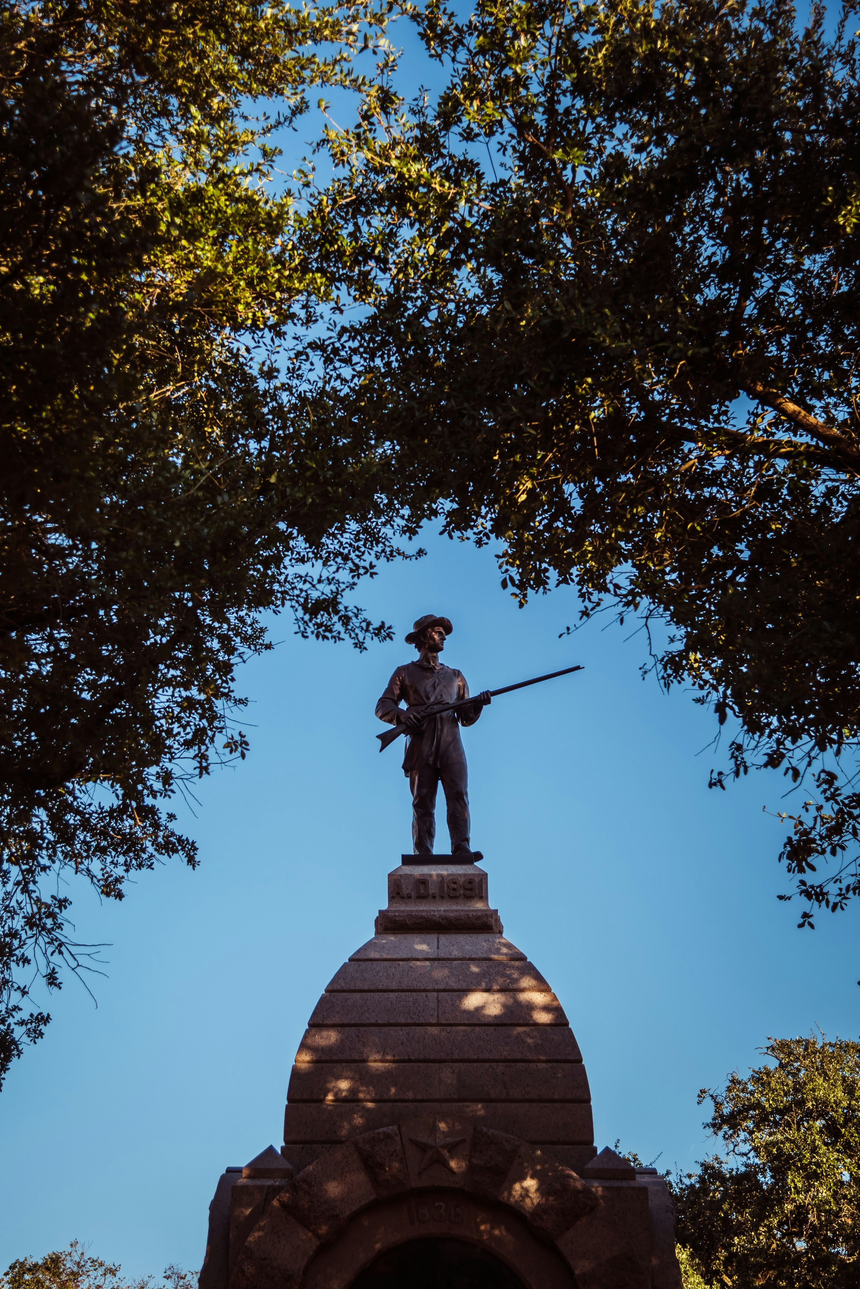 A statue of a man holding a rifle on top of a building photo – Free ...
