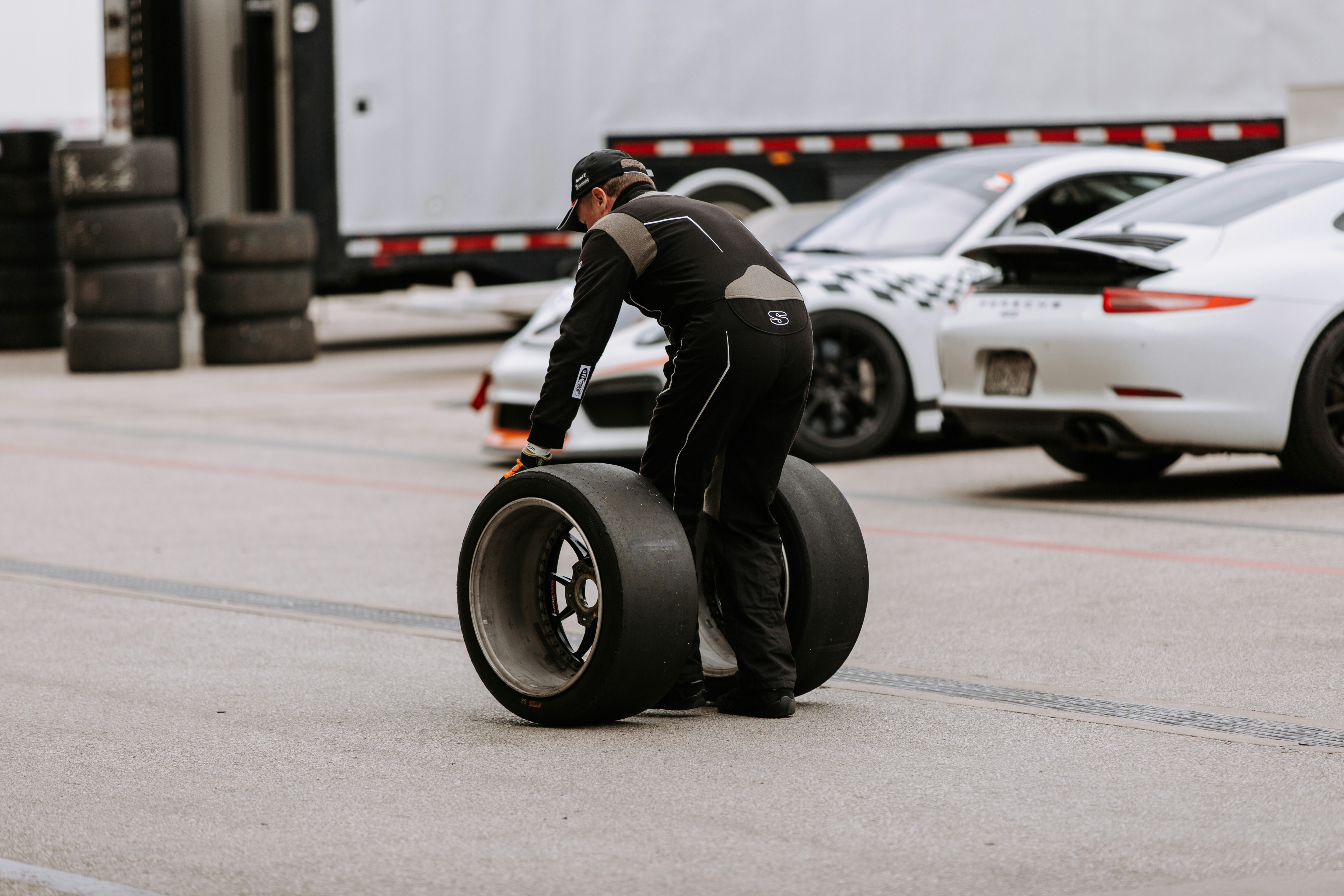 A tire technician prepares racing tires in a pit lane, highlighting the behind-the-scenes efforts essential for competitive motorsport.