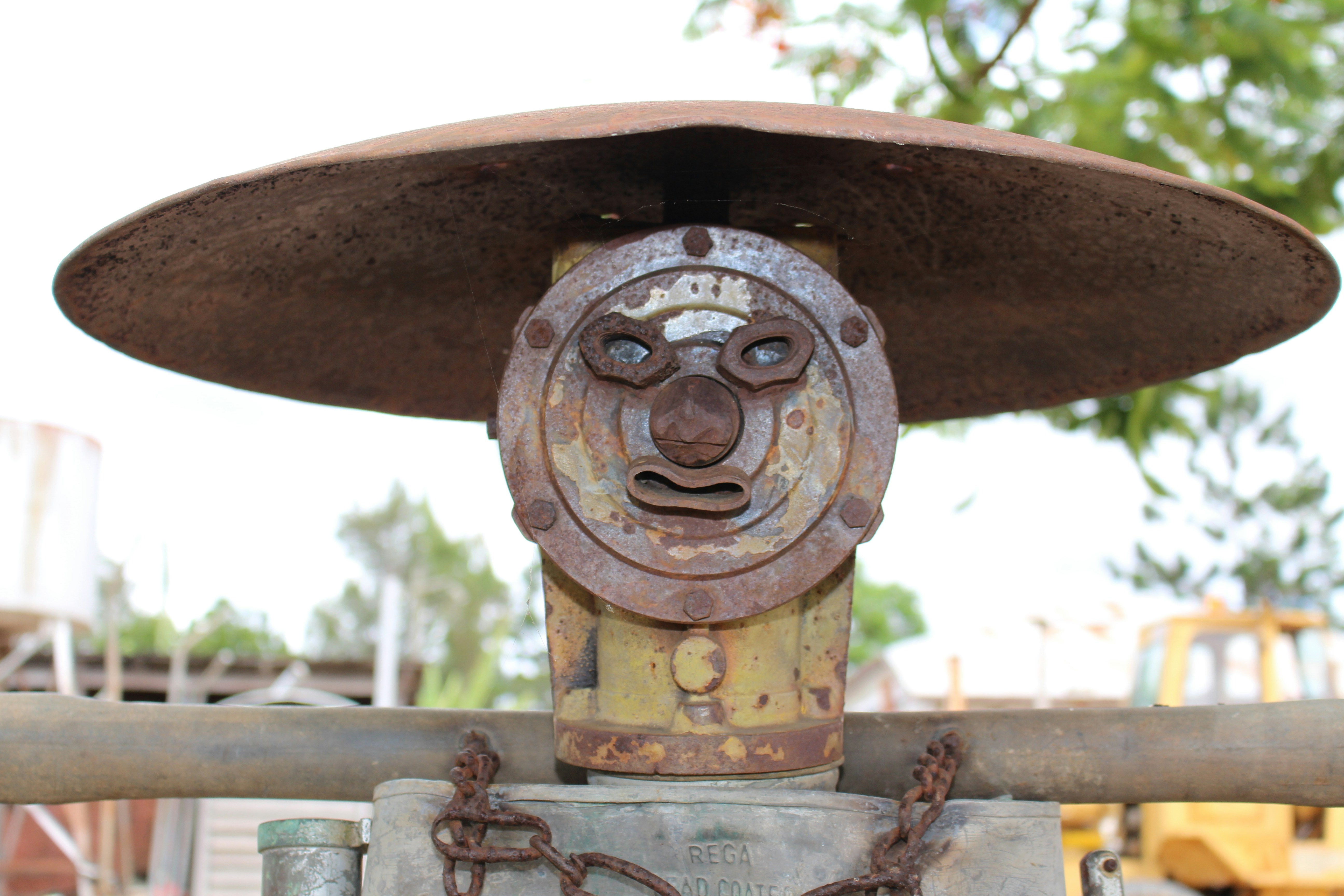 Grinning Valve: A Rusted Circular Disc in an Industrial Yard