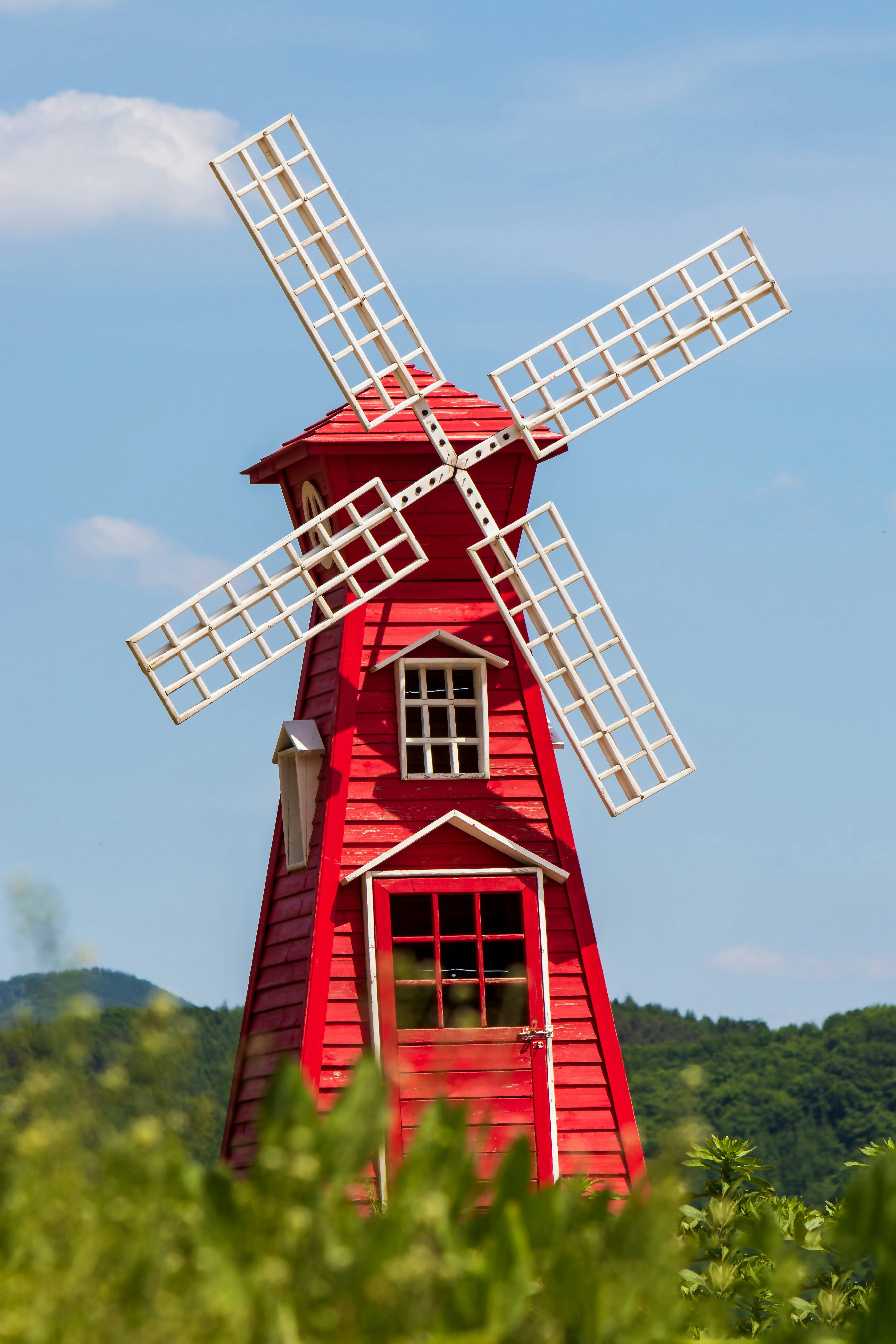 Red Windmill Rising: A Rustic Monument Among Greenery
