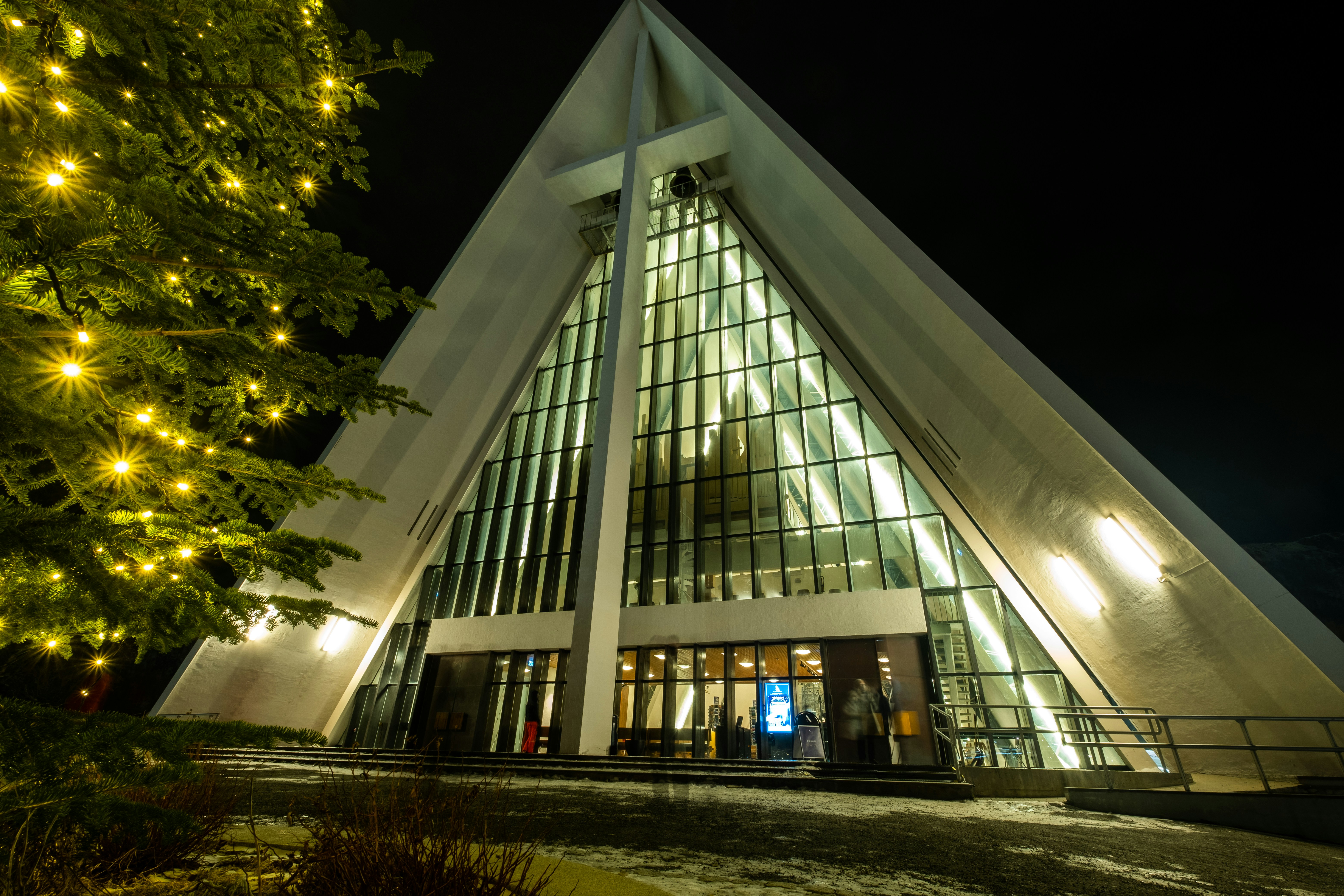 A-frame Glass Cathedral at Night: Entrance Illuminated Beneath a Triangular Facade