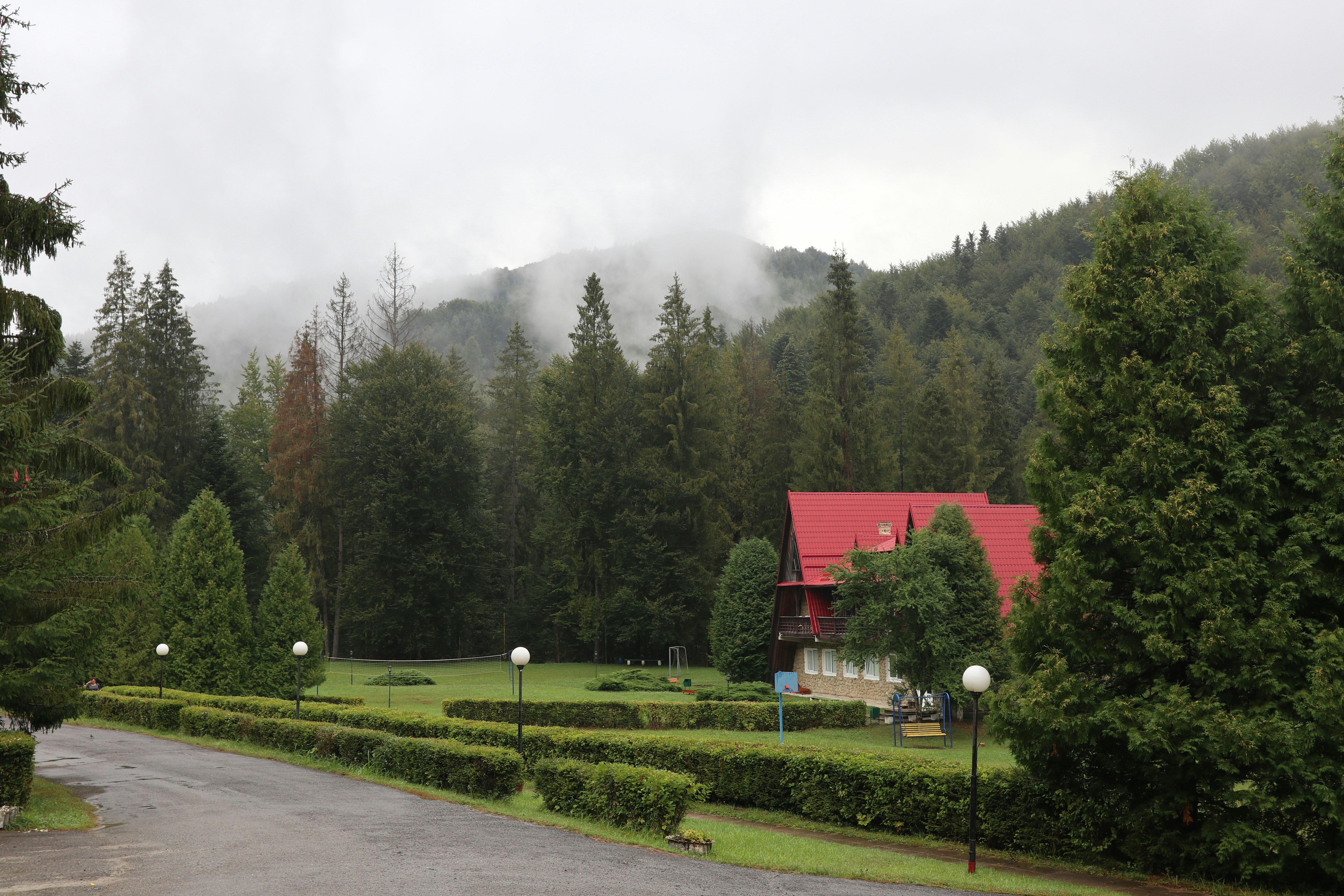 Red-Roof Lodge Emerges Through Fog in a Quiet Parkland