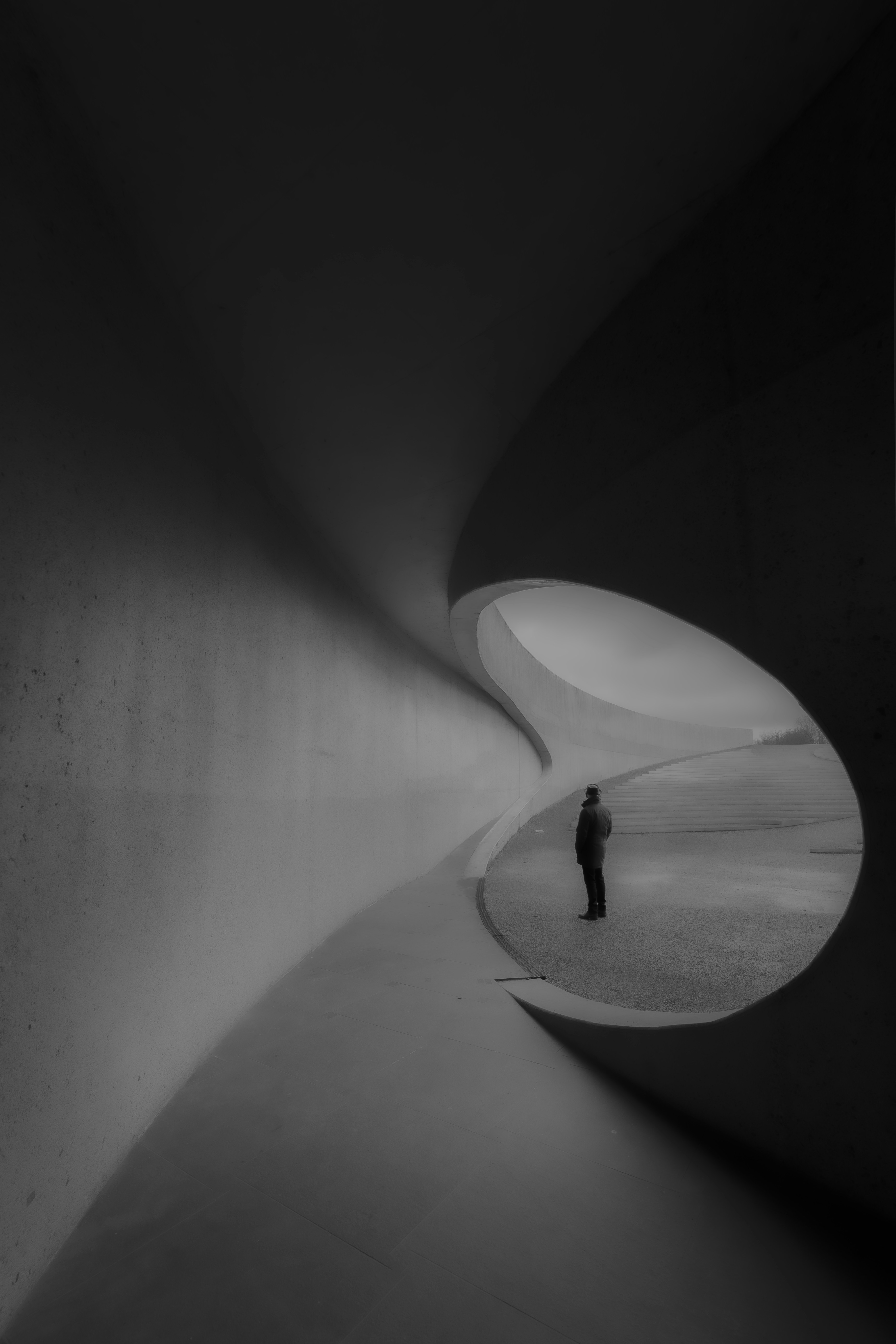 Within the Circular Arc: A lone silhouette in a sculpted concrete tunnel