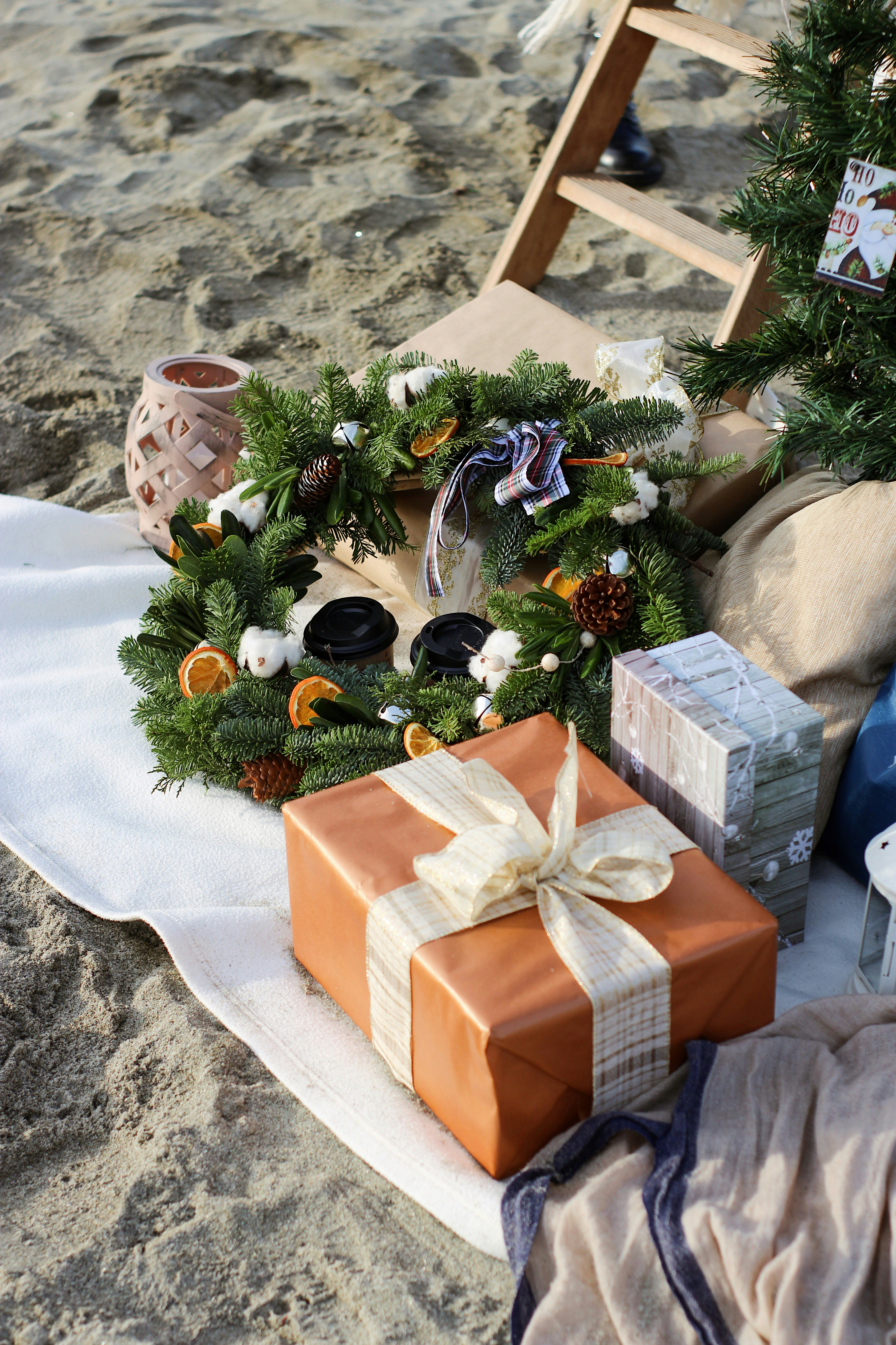 a wreath and presents on a towel on the beach