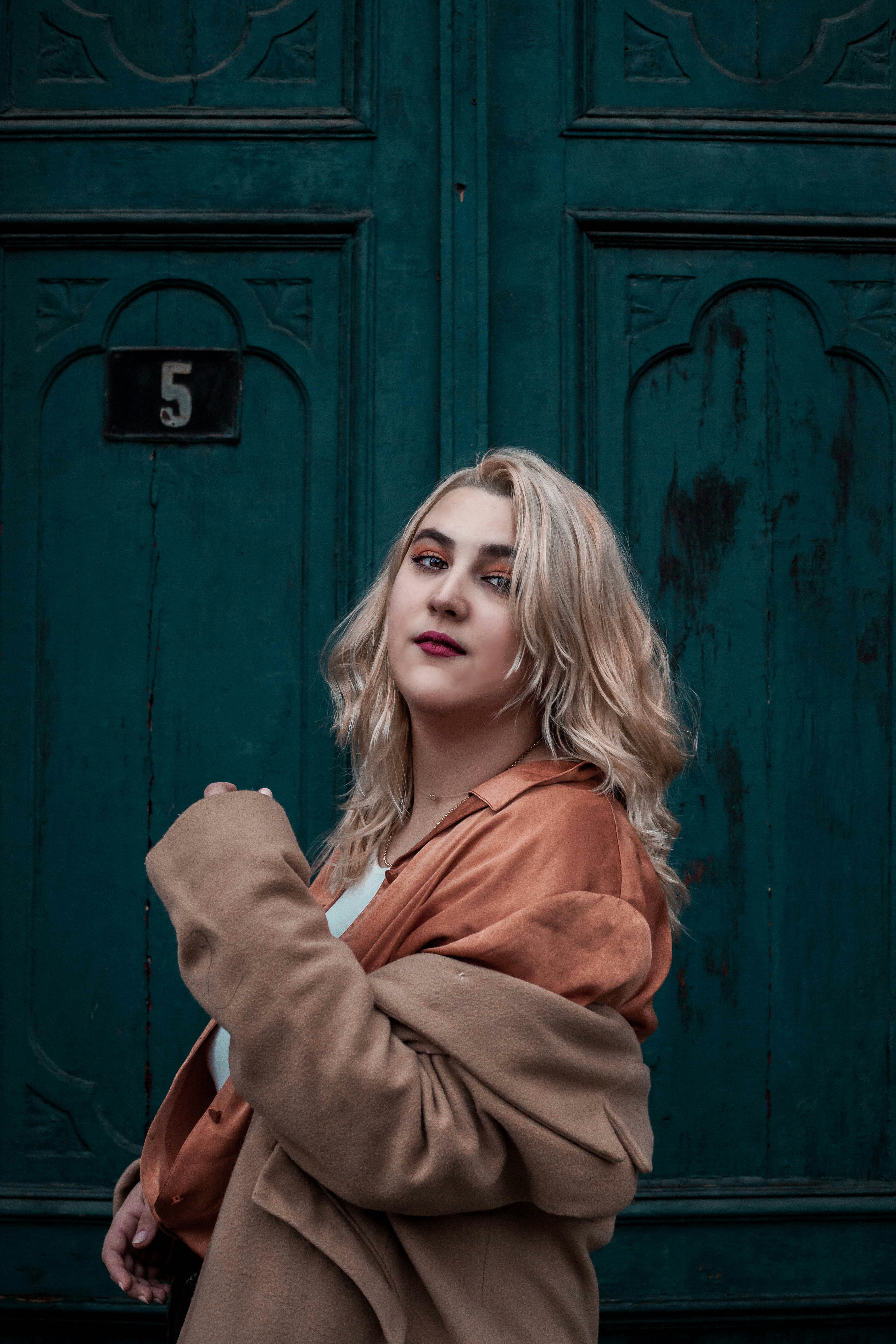 Blonde in Terracotta and Teal: Portrait Before an Aged Door