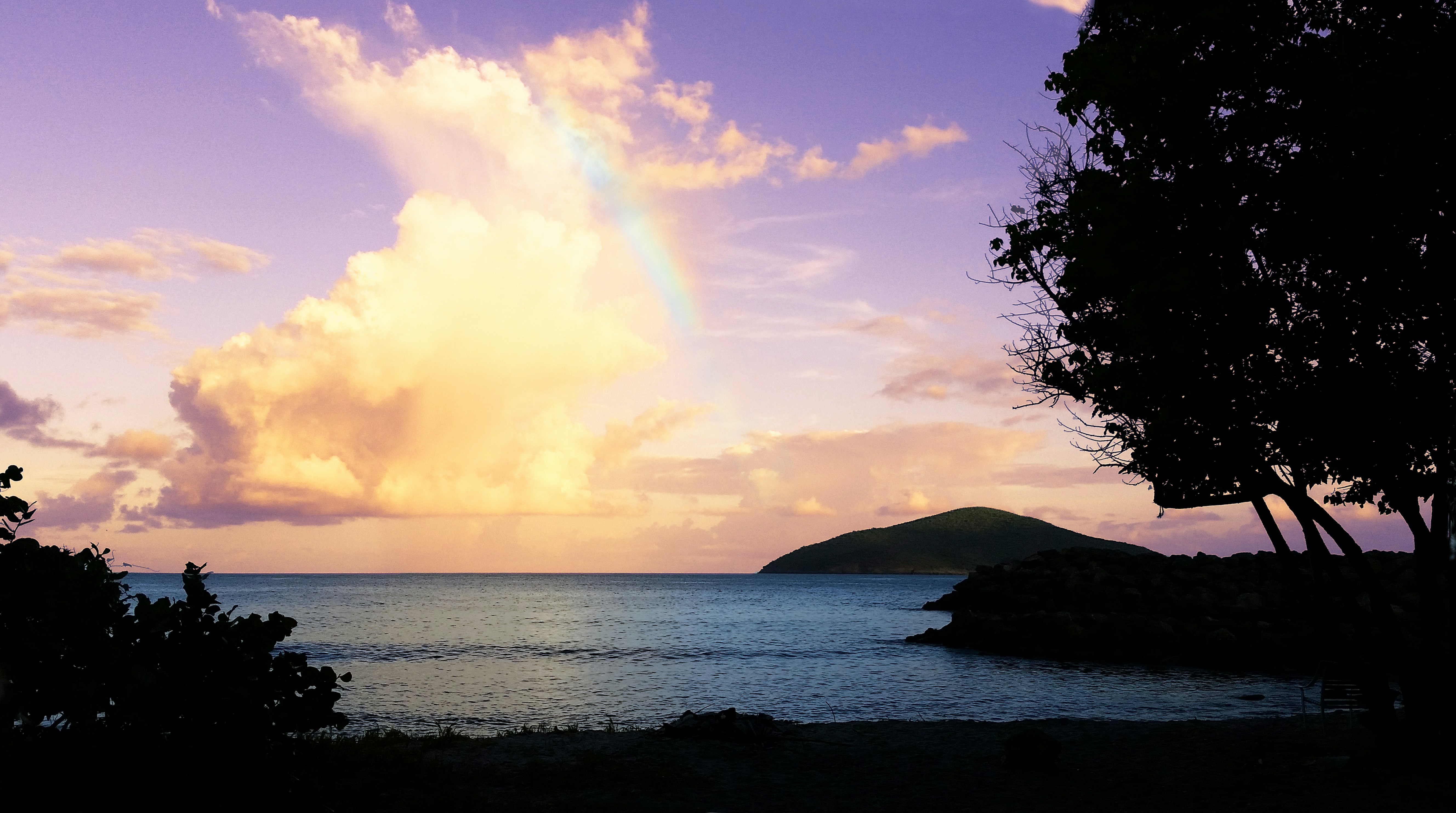 Distant Rainbow Over Quiet Shore at Sunset