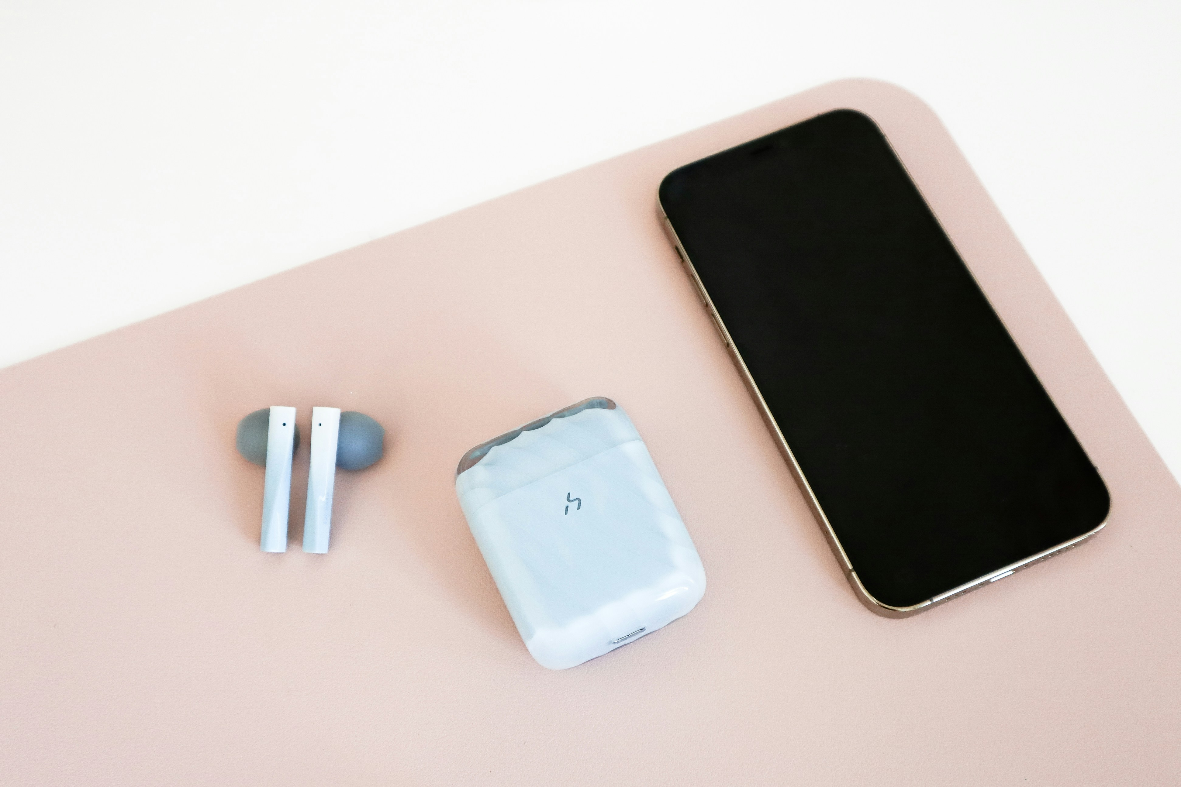 A cell phone, ear buds, and a charger on a table photo – Free Iphone ...