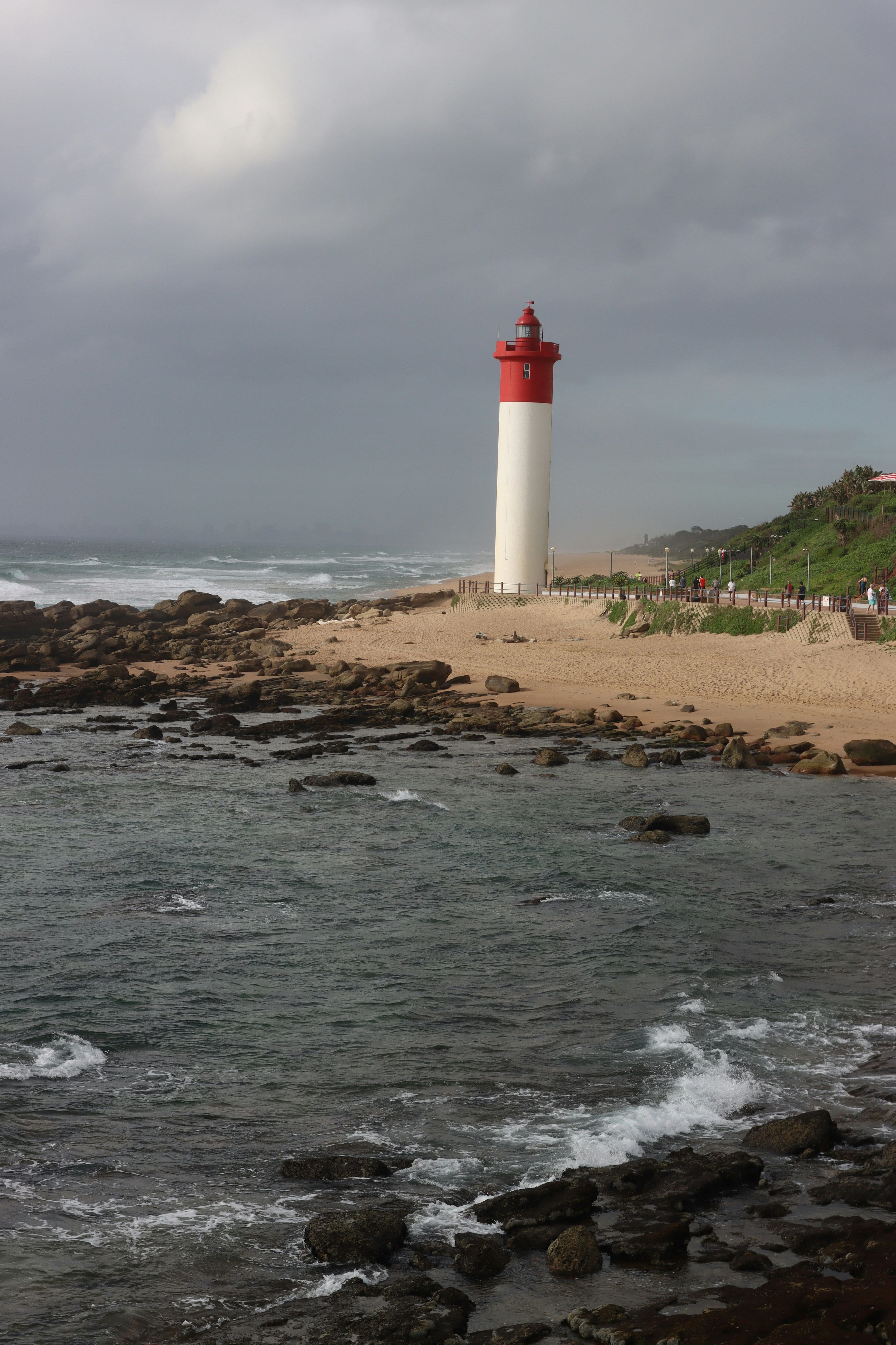 A red and white lighthouse sitting on top of a sandy beach photo – Free ...