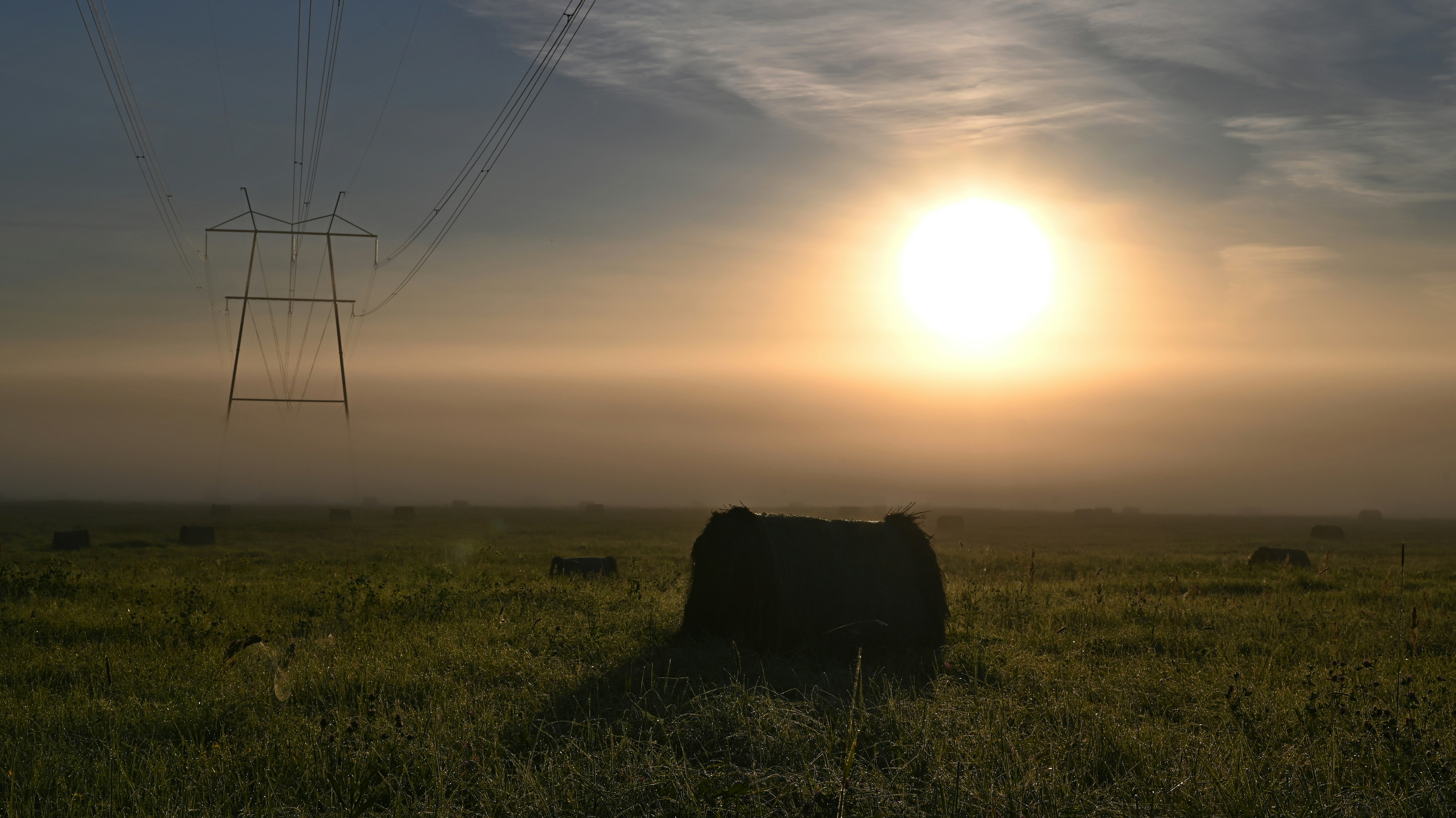 Dawn's Quiet Arc: Hay Bale Beneath a Misty Sunrise