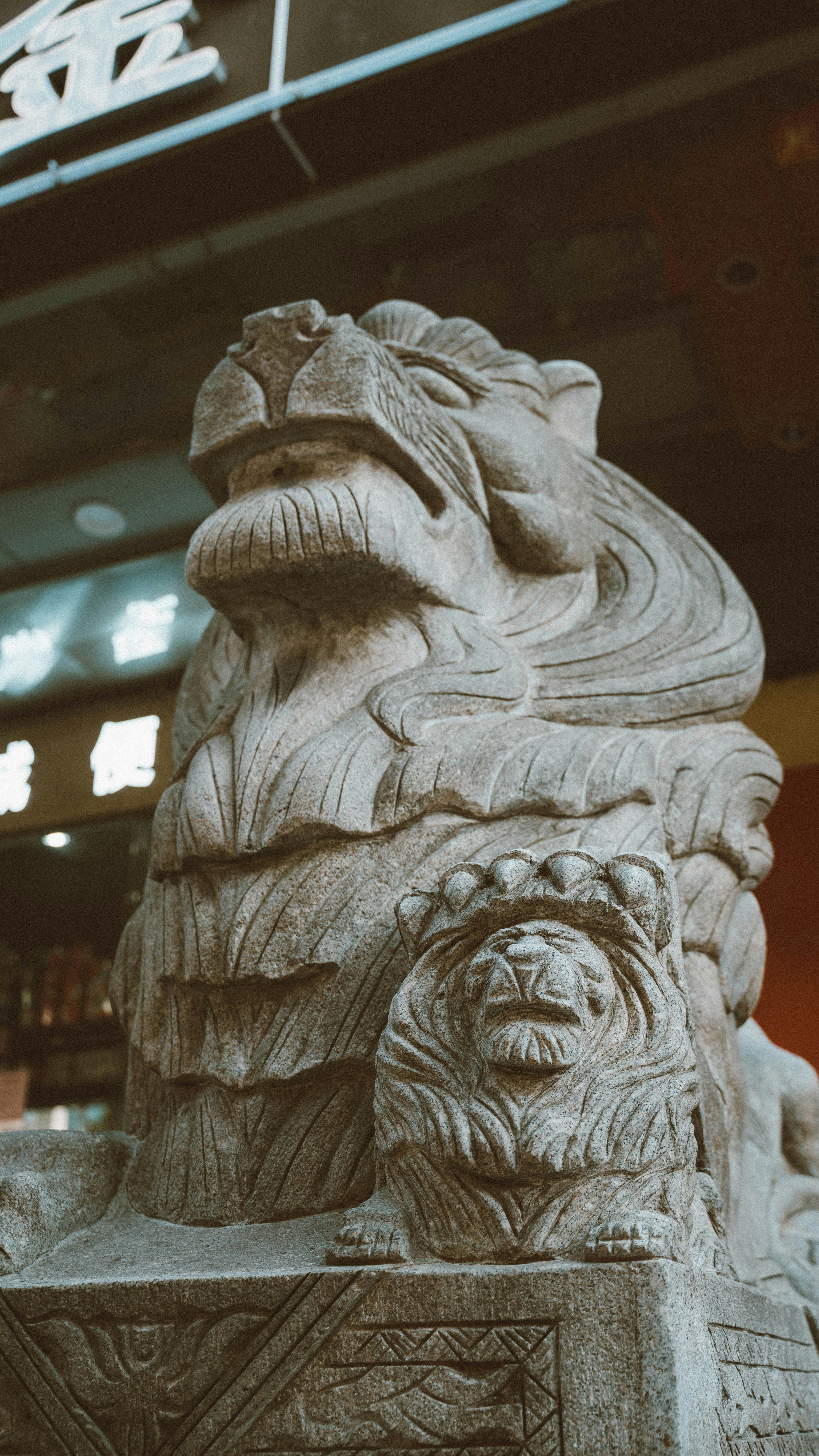 Intricately carved stone lions stand sentinel, showcasing detailed artistry and cultural significance. The larger lion exudes strength, while the smaller one adds a touch of whimsy.