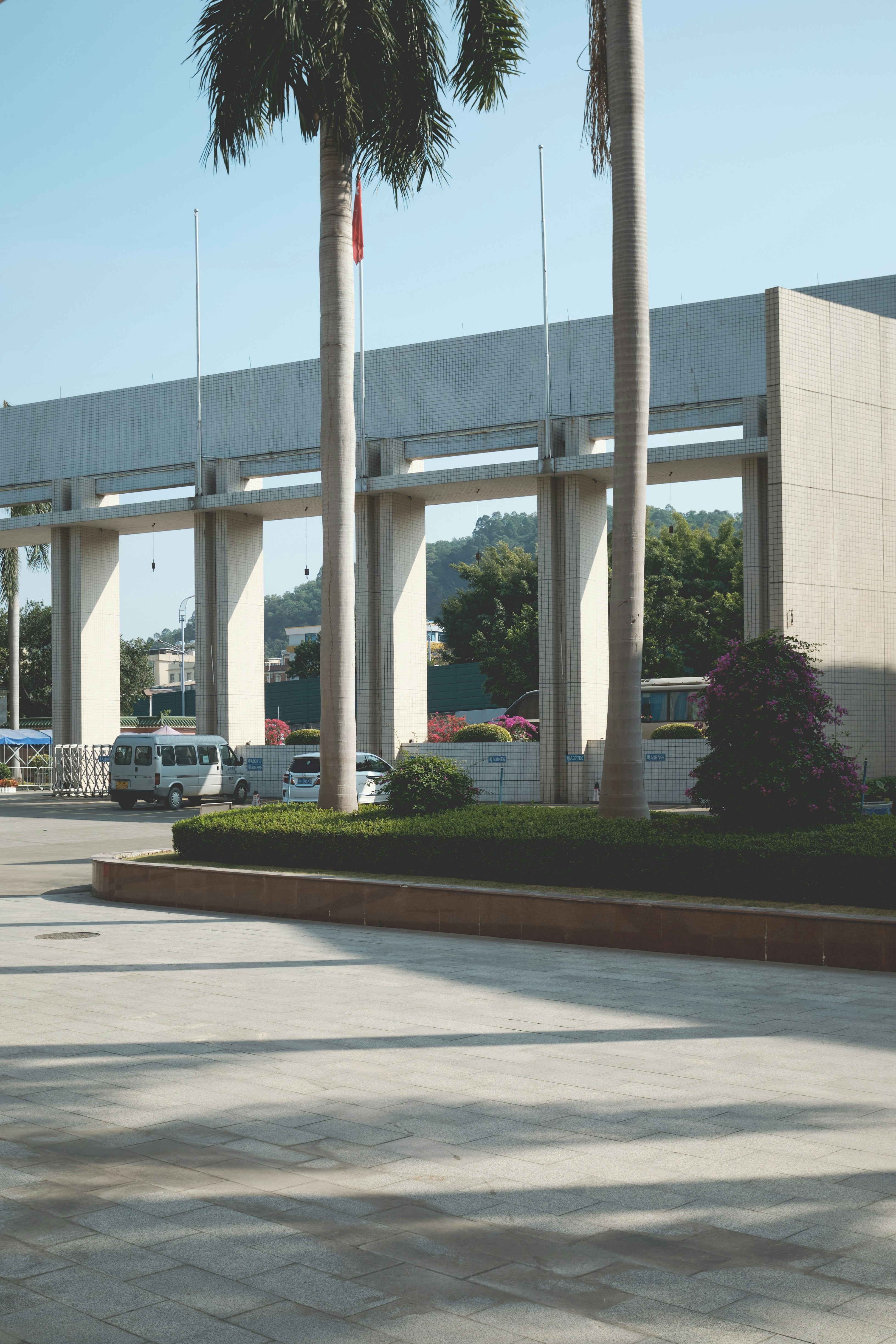 Modern architectural structure framed by palm trees and lush greenery, showcasing a blend of urban design and natural beauty.