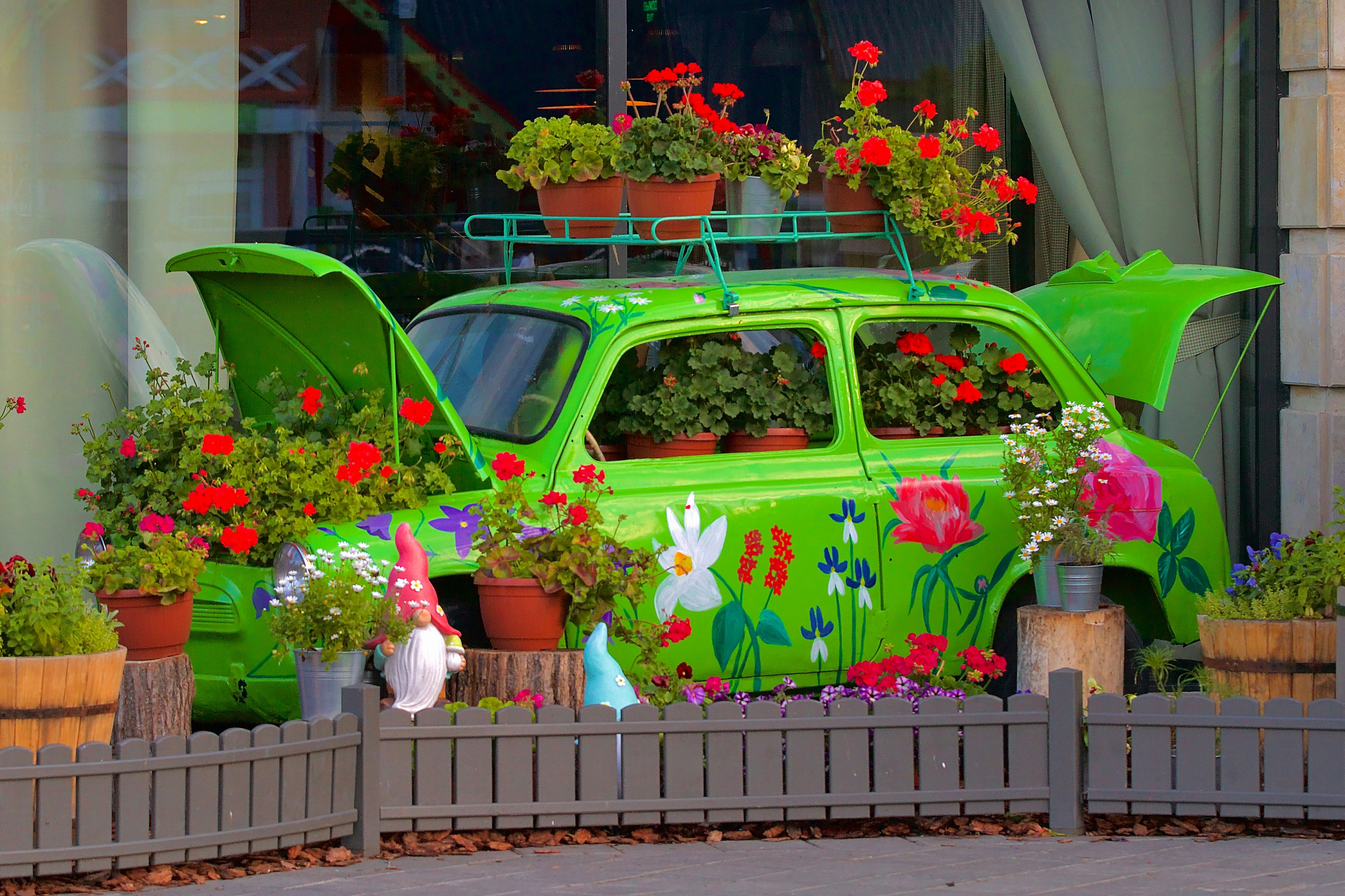 a green car is decorated with flowers and potted plants