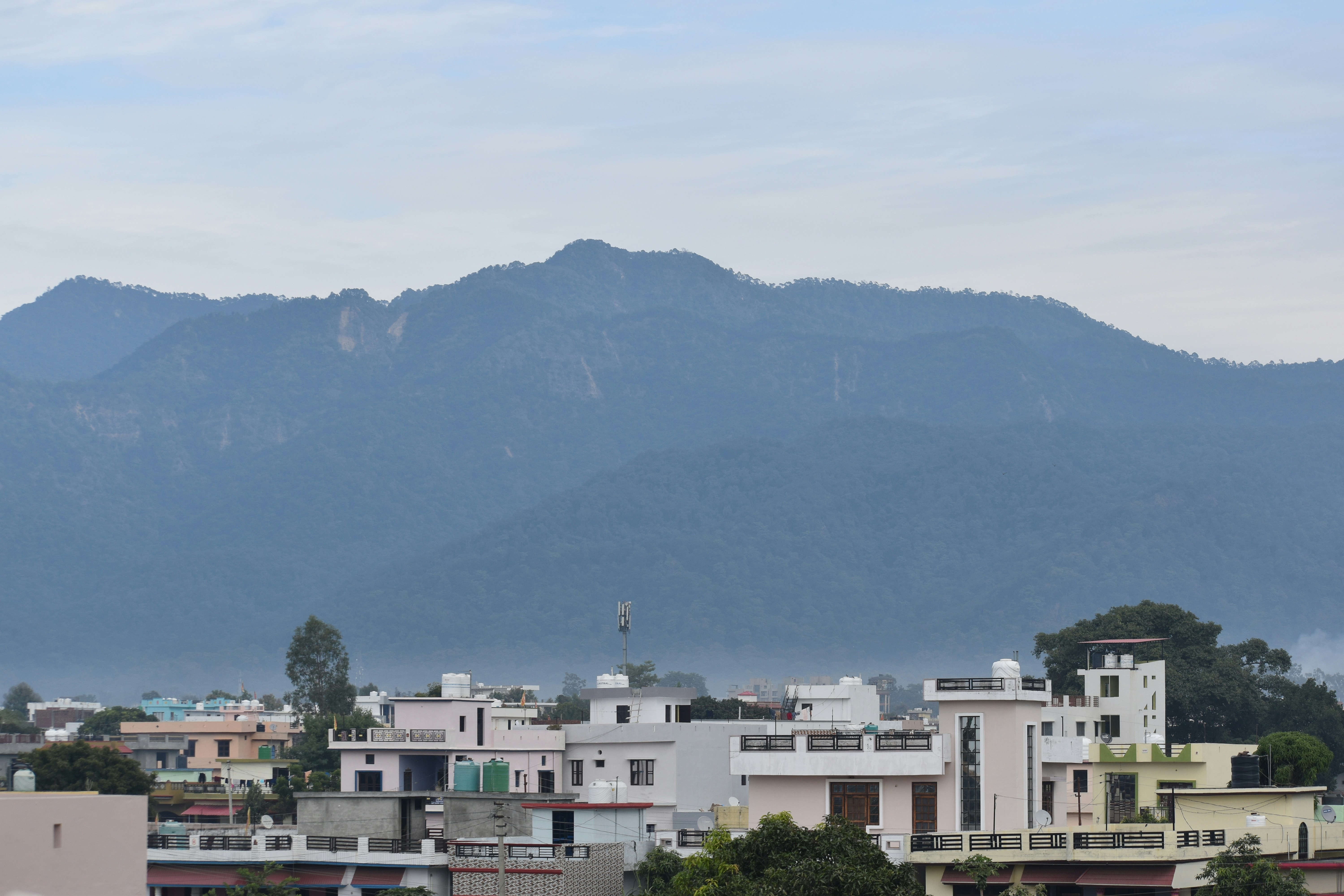 Cityscape with buildings in the foreground and a mountain range under a clear sky.