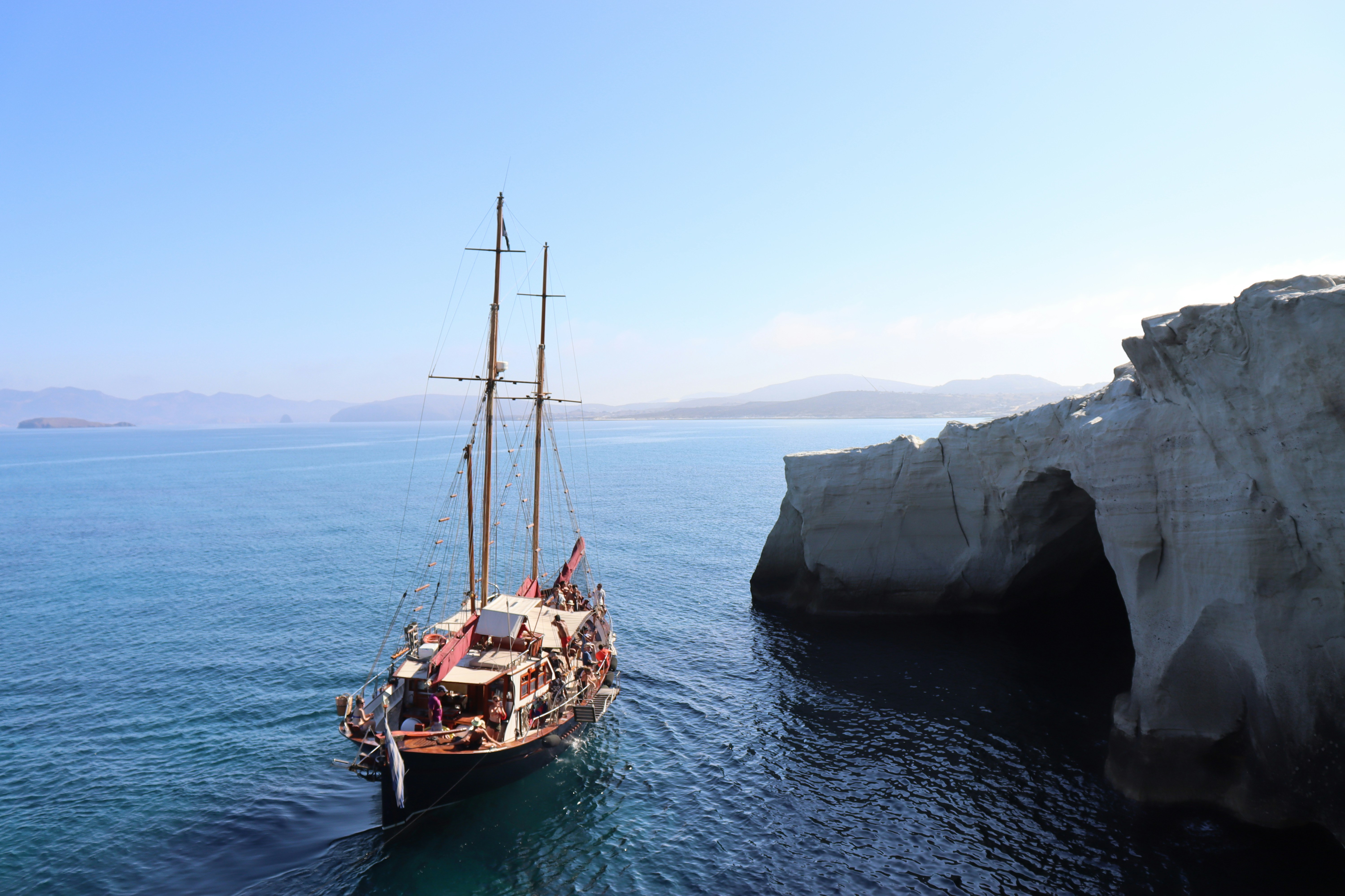 A boat in the water near a large rock formation photo – Free Outdoors ...