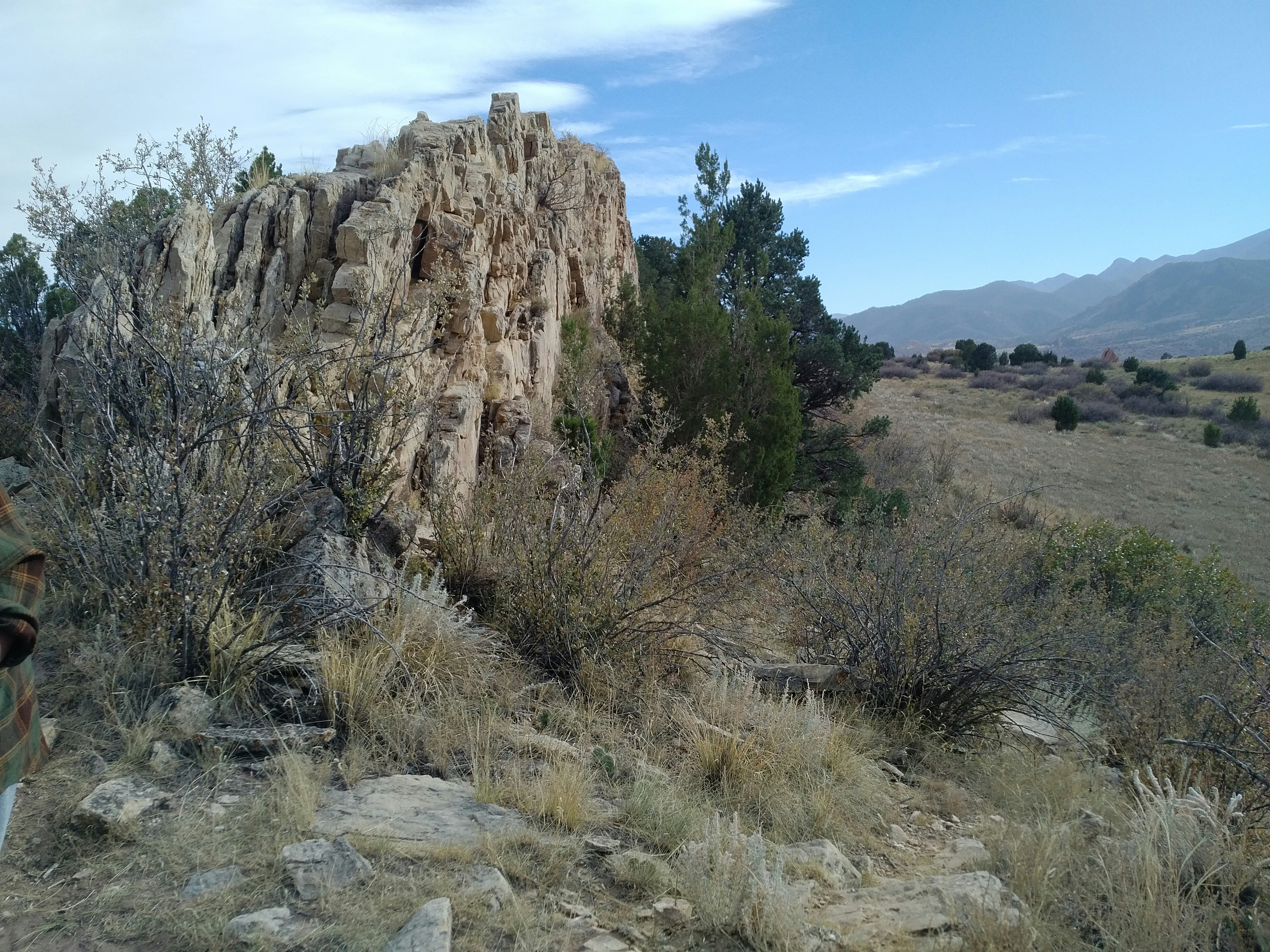 Rocky outcrop surrounded by sparse vegetation under a clear sky, showcasing the rugged beauty of the landscape.