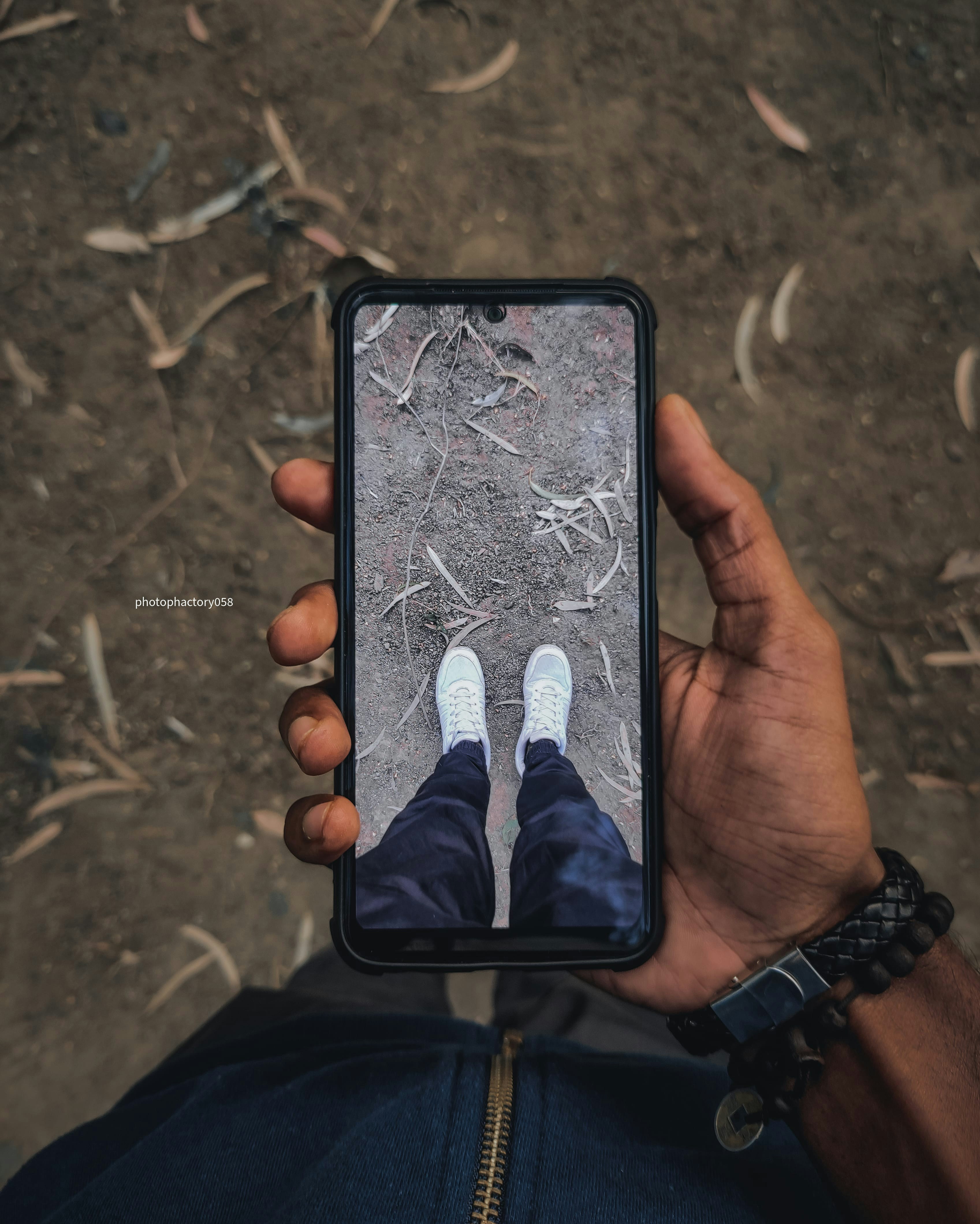 A person holding a cell phone with a picture of someone's feet photo ...