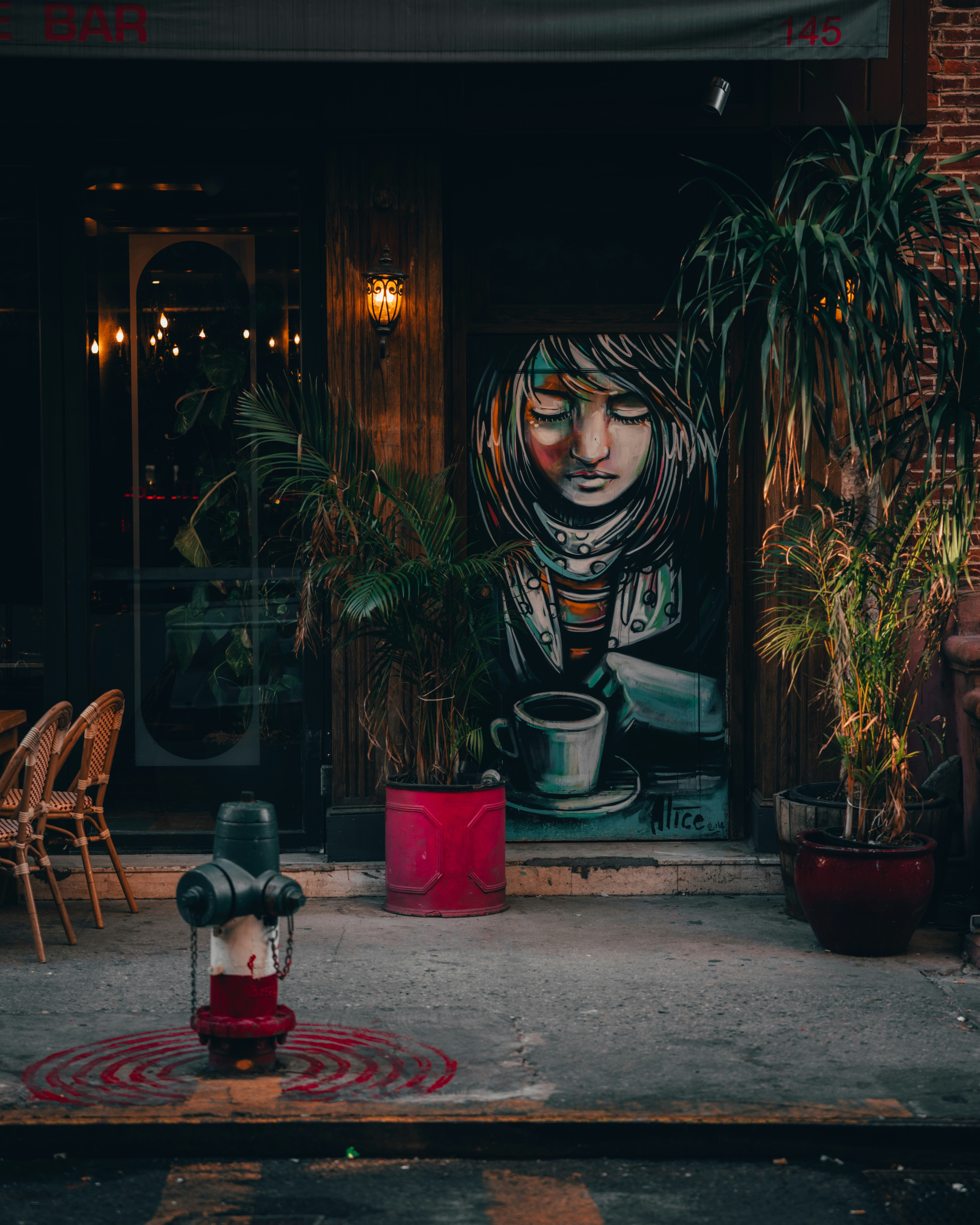 Cradled Cup: A mural portrait framed by urban ferns outside a dim café