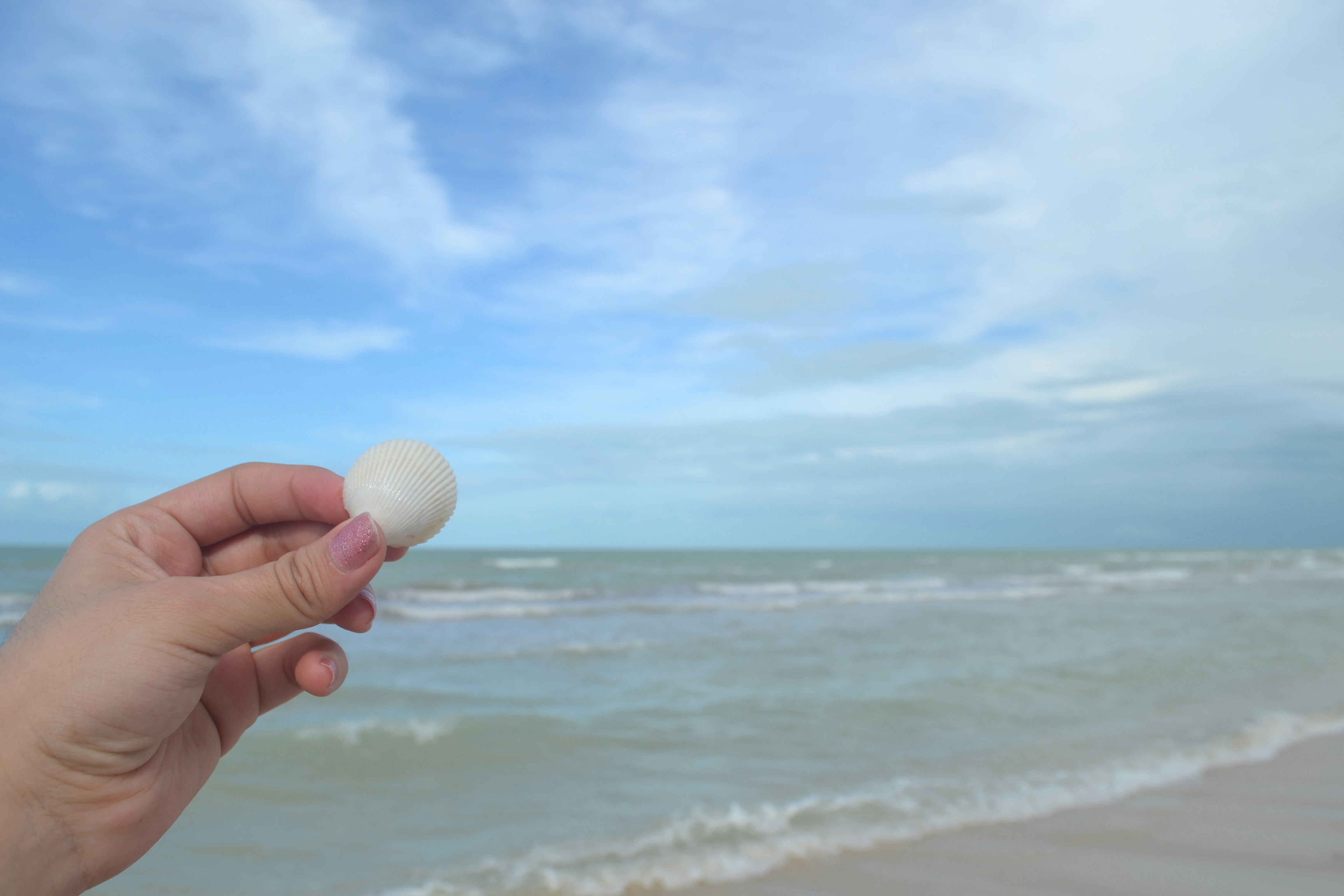 Inlet of Calm: A Hand-Held Golf Ball Framing a Quiet Beach Horizon