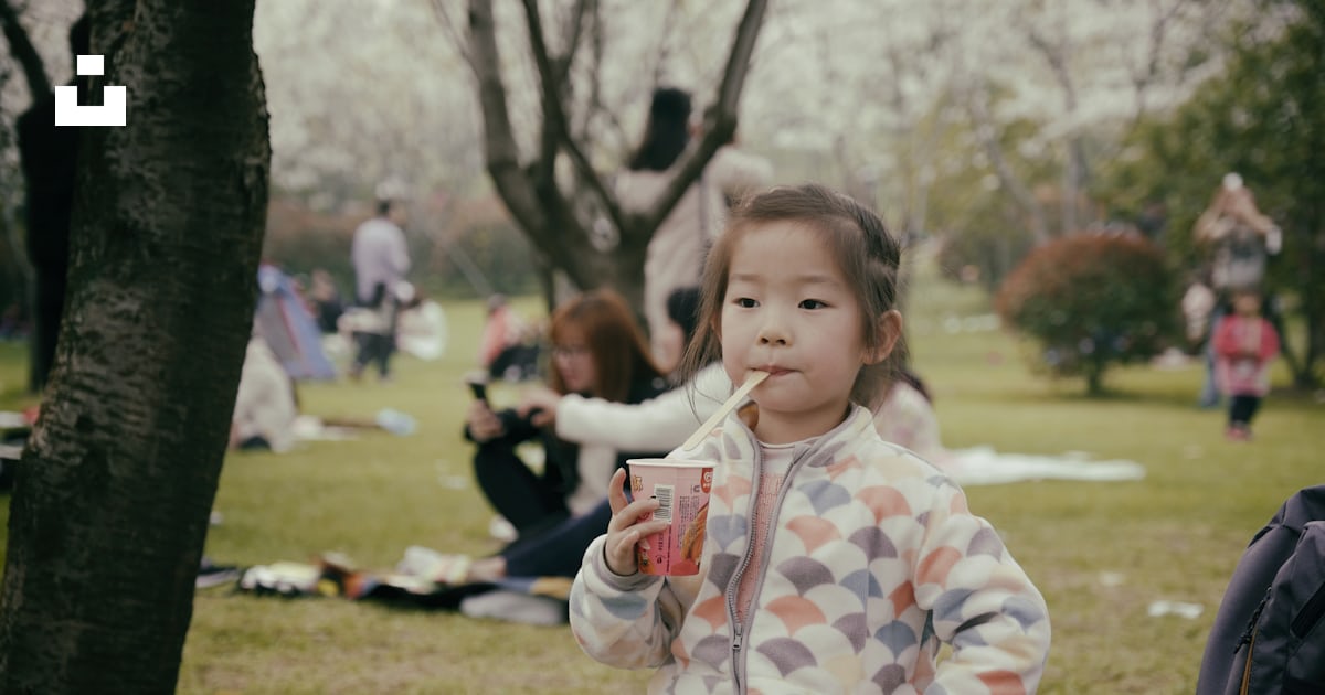 공원 벤치에 앉아 음료를 마시는 어린 소녀 사진 Unsplash의 무료 음식 이미지