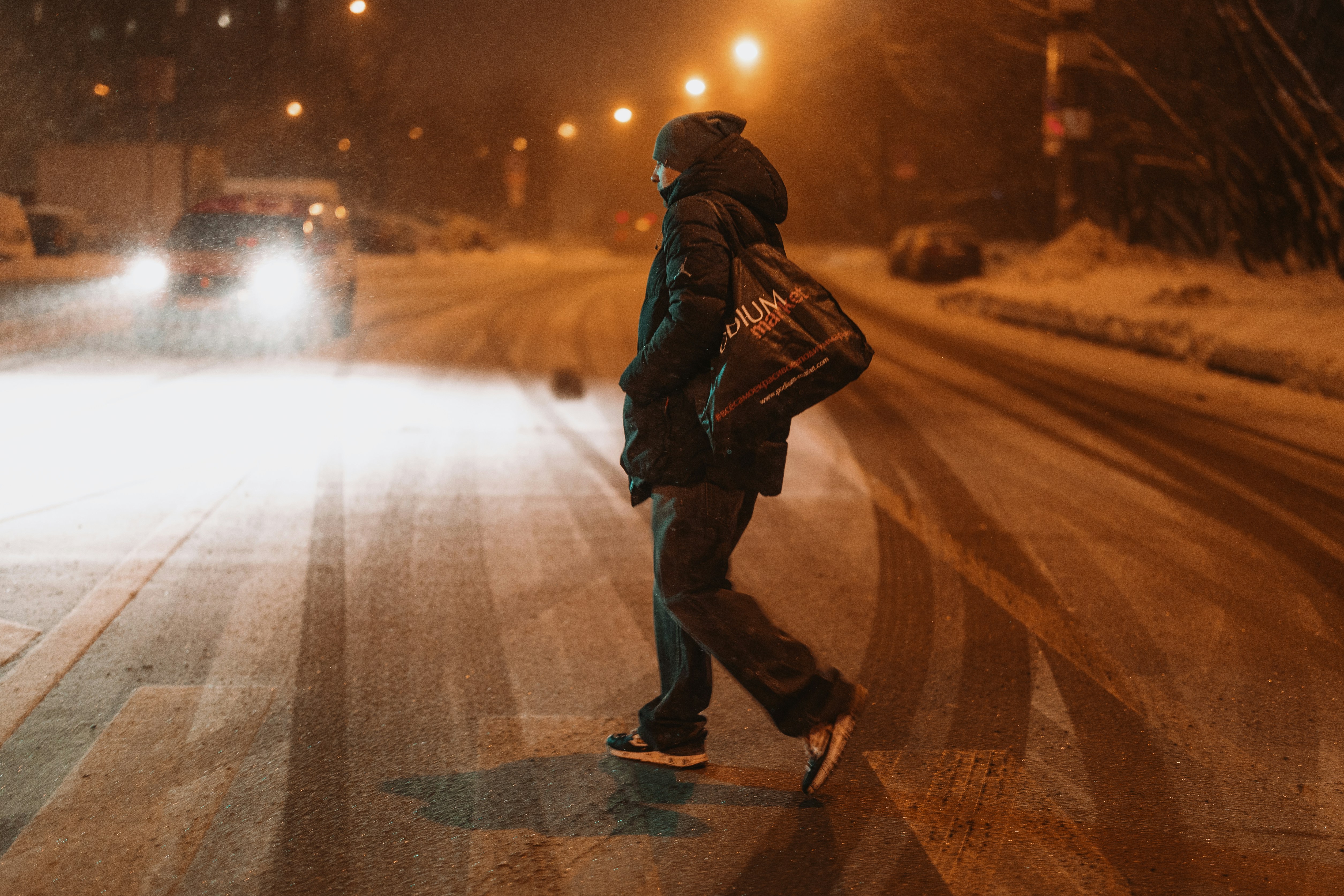 Snowlit Crosswalk: A Lone Pedestrian Under City Glow