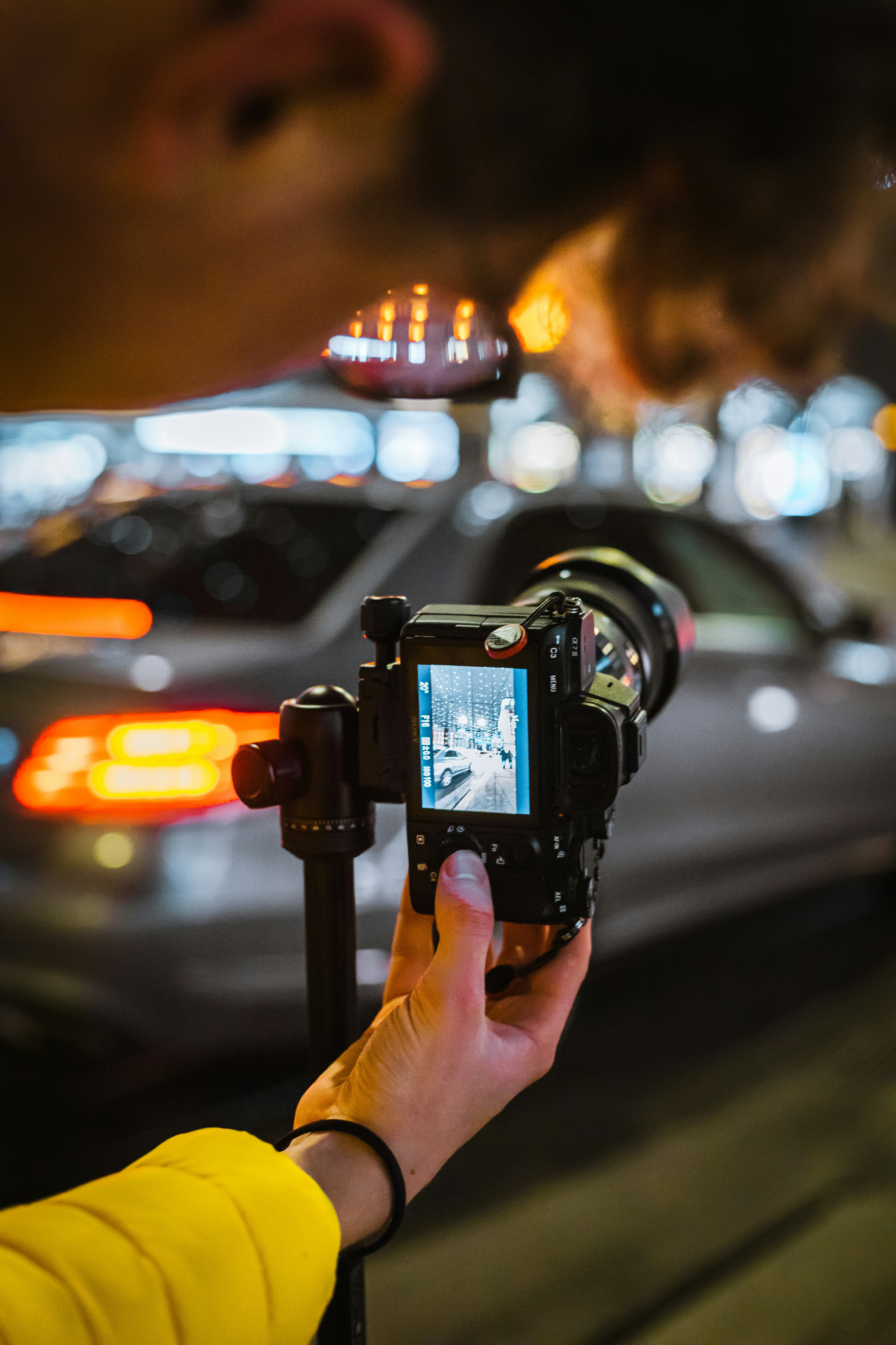 Glimmer of Focus: A photographer's handheld rig aims at a distant glow
