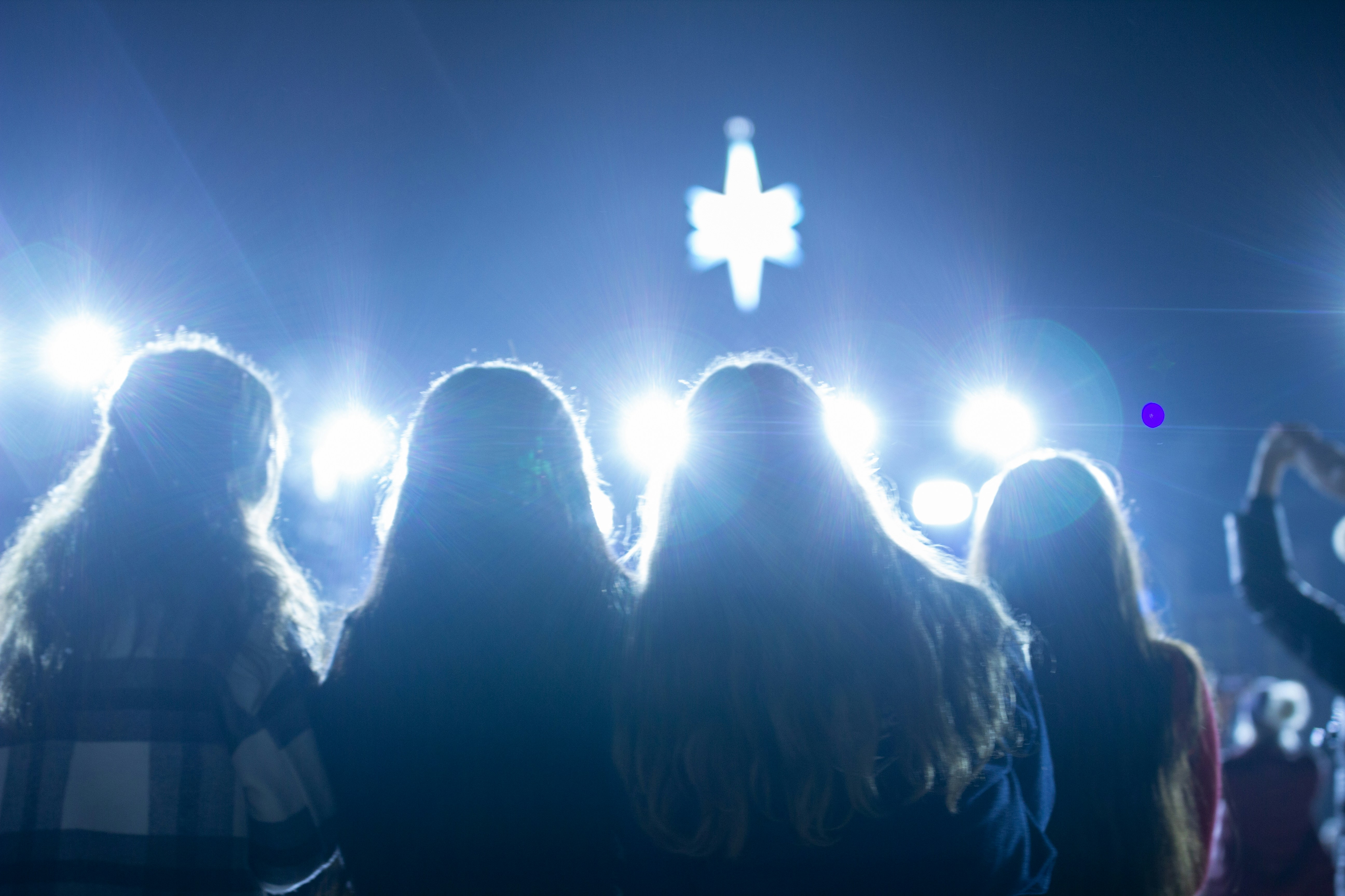 Backlit Constellation: silhouettes rise against a halo of stage light