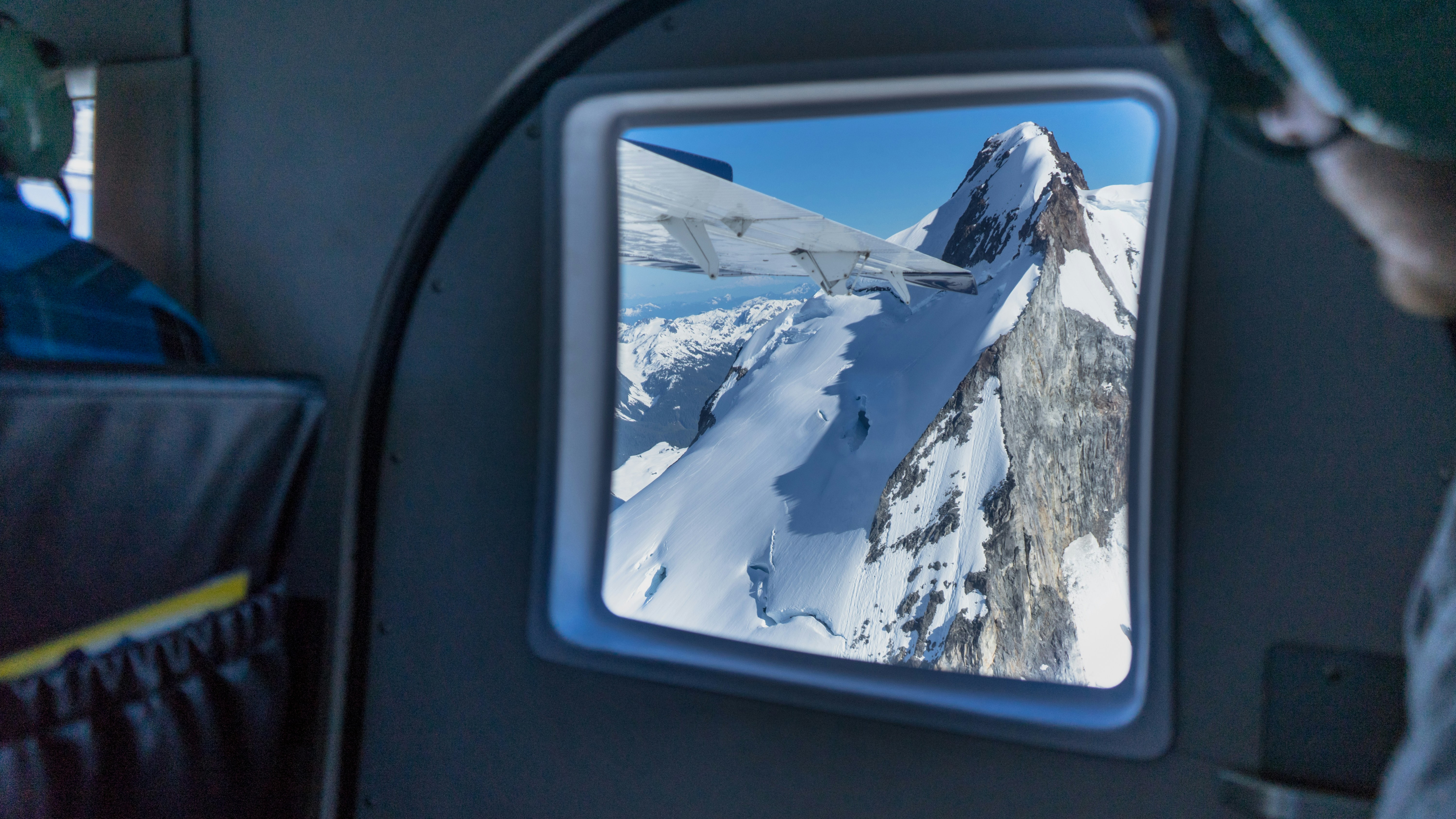 Windowed Summit: Snow-Capped Peak Seen Through a Passenger Seat Window