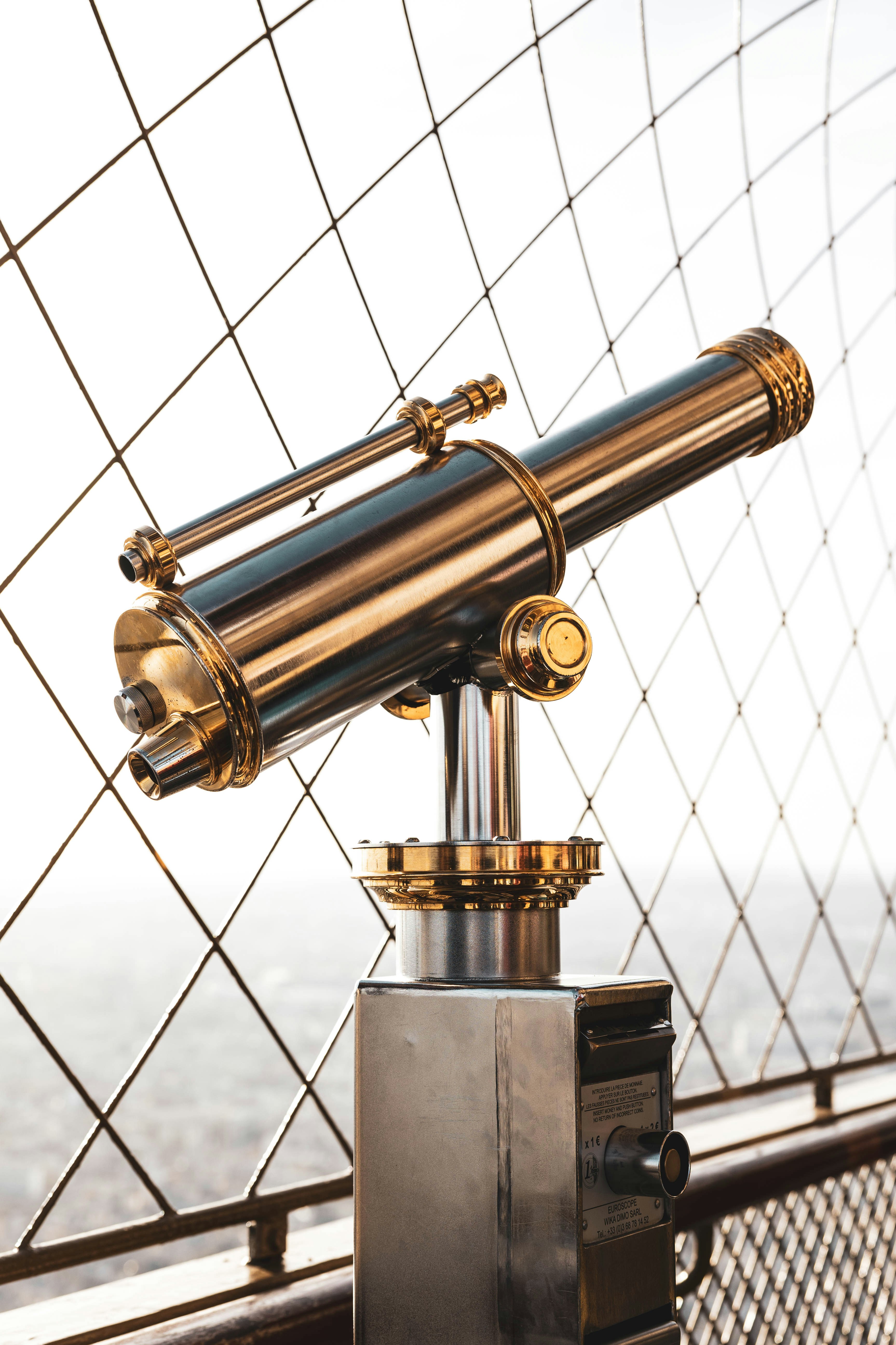 Brass Sentinel Over Diamond Mesh: A Vintage Telescope Framing the City Beyond