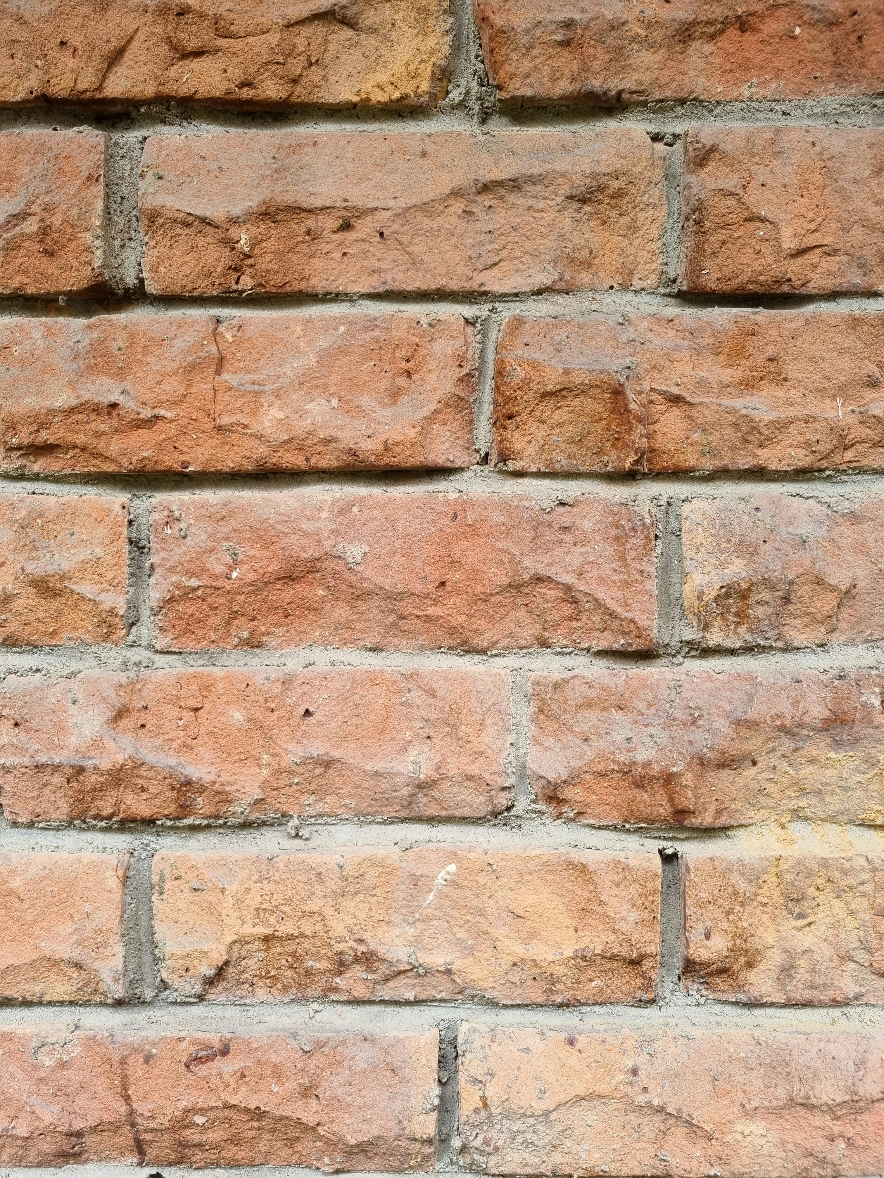 Close-up of a rustic brick wall showcasing varying shades and textures of the bricks. The image highlights the craftsmanship and character inherent in traditional masonry.