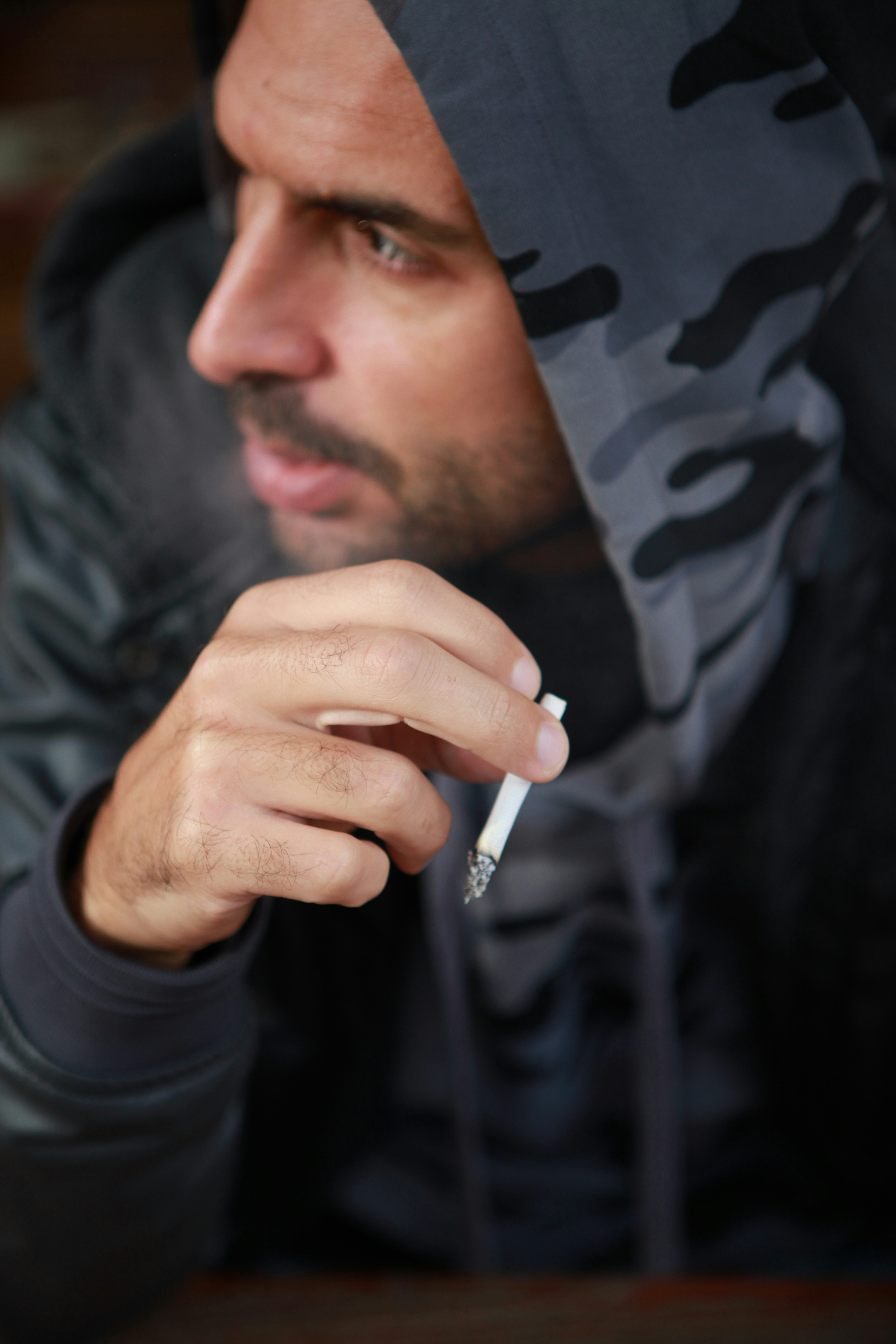 Hooded Focus: Smoke Framed by Camouflage in a Close-Up Portrait
