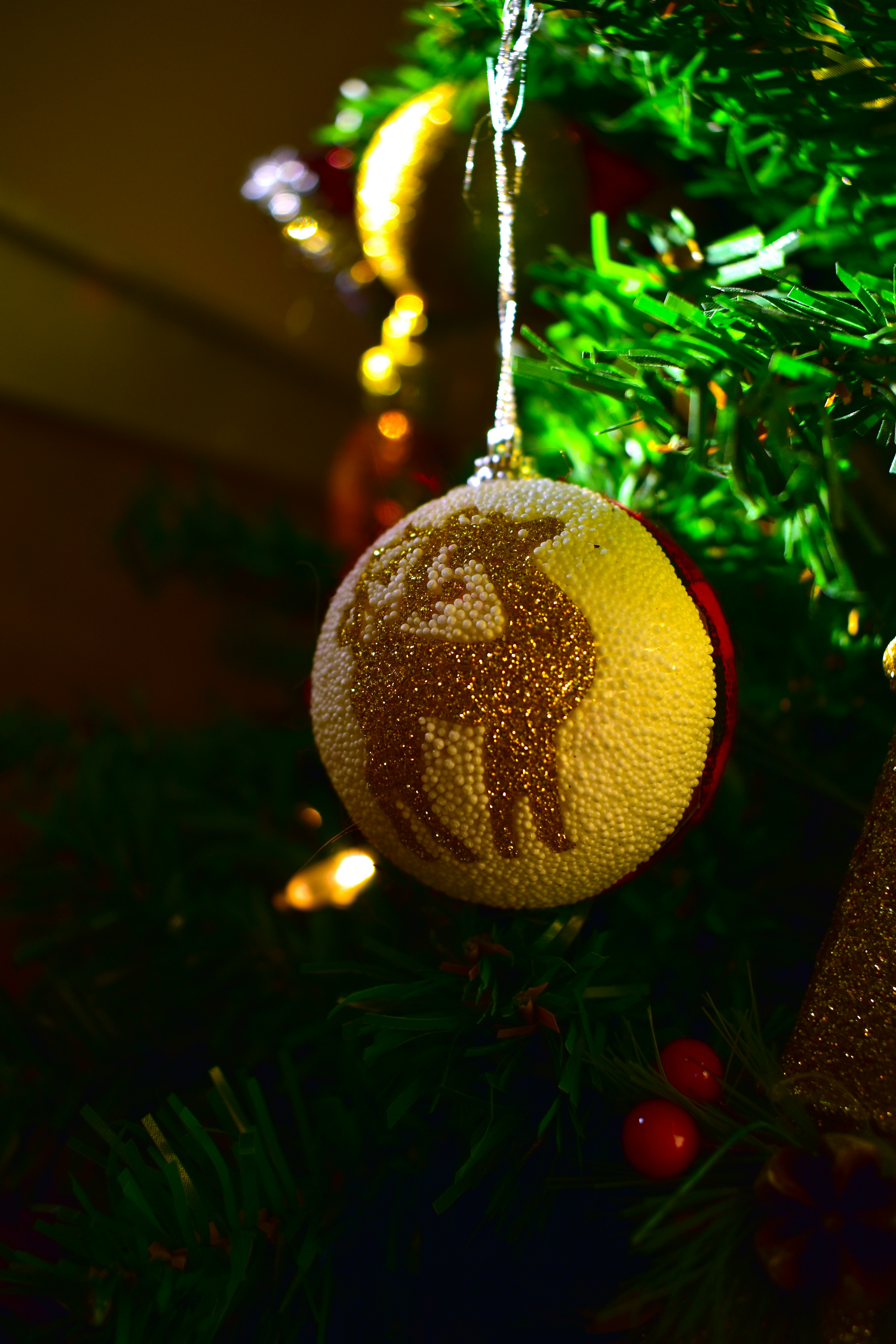 Glowing ornament with reindeer silhouette on a festively illuminated tree