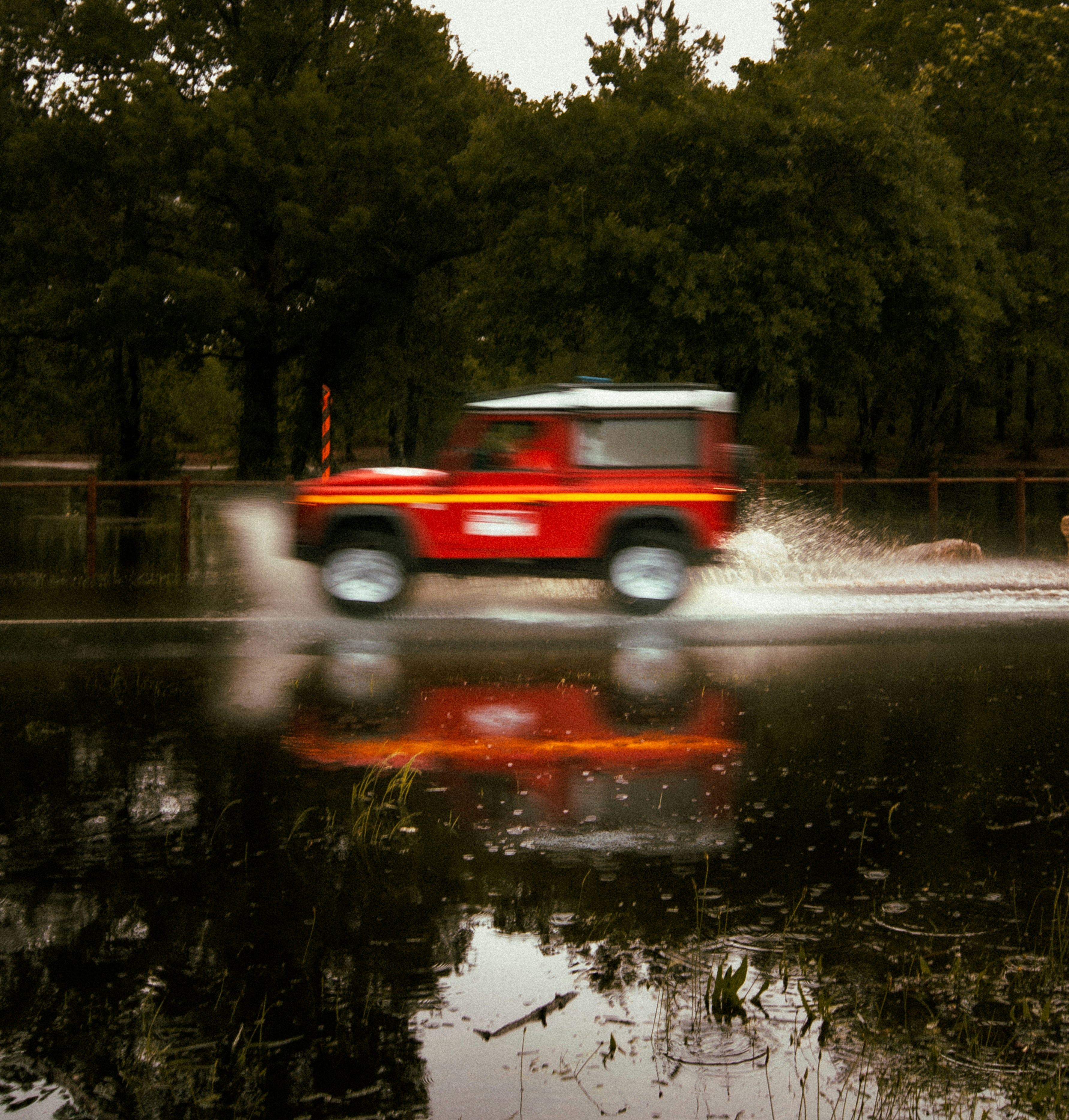 Red Ember on Wet Asphalt: Fire Truck Blurs Across a Flooded Street