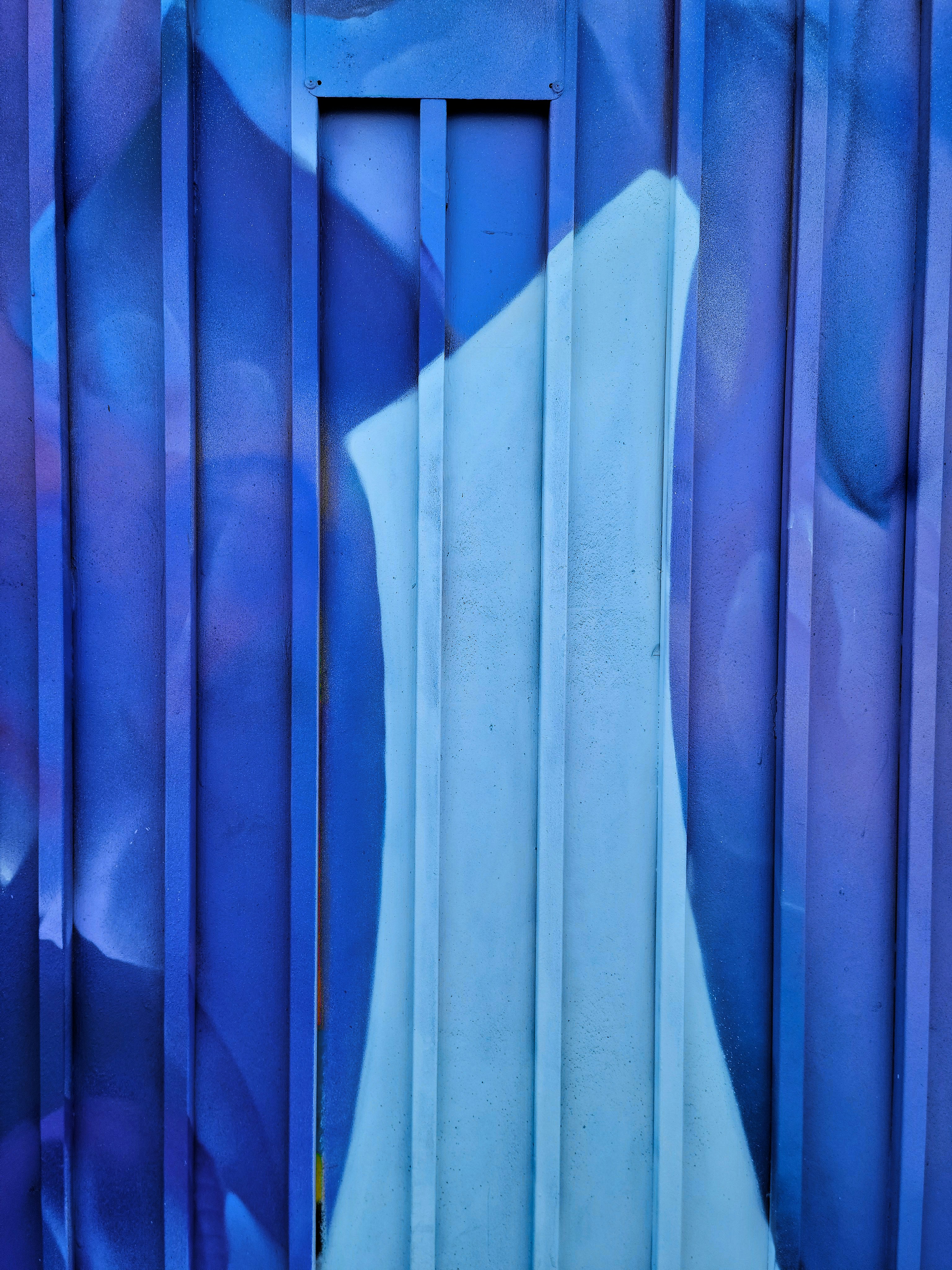 Intricate blue graffiti art on a corrugated surface, showcasing layered textures and vibrant hues.